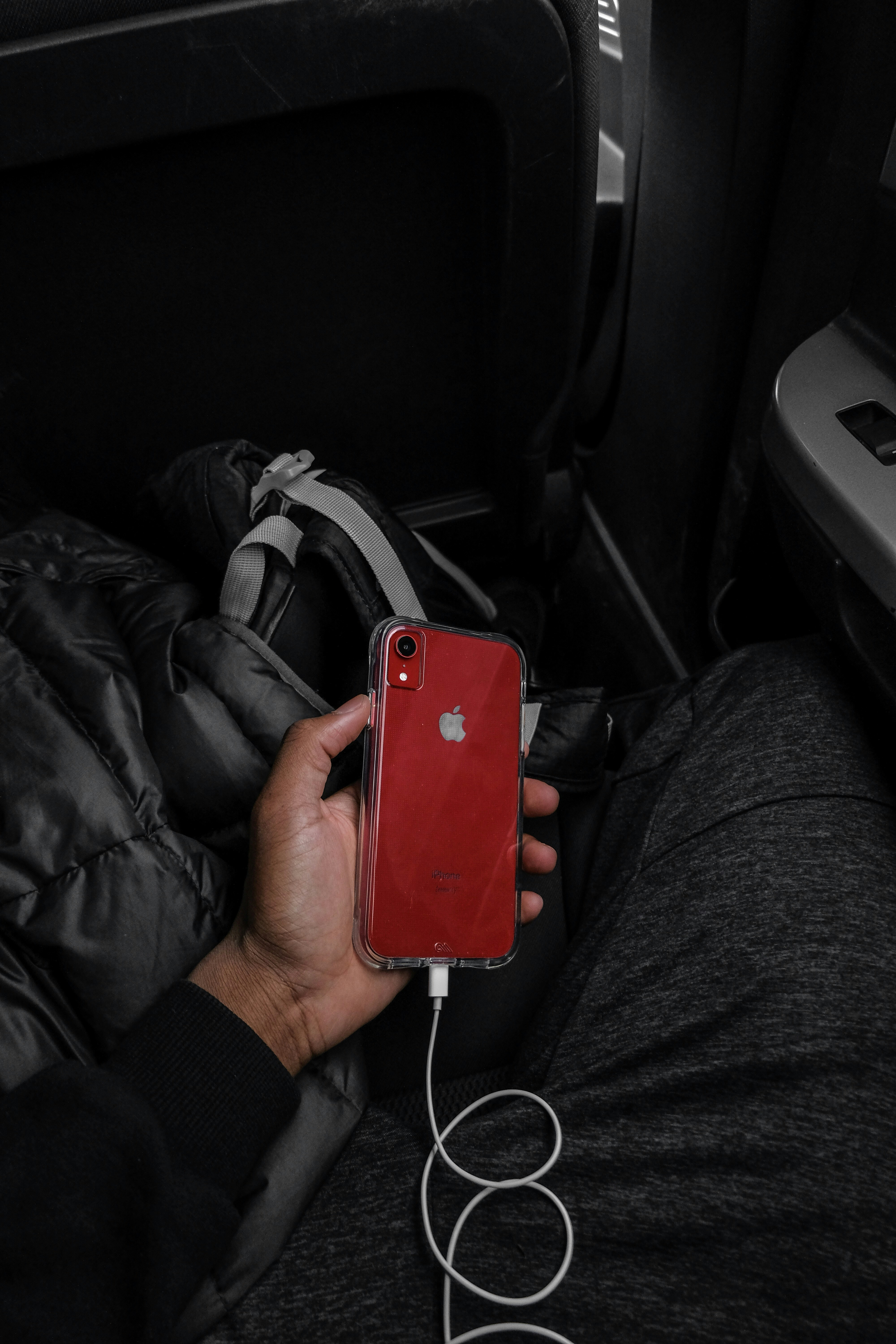 Red iPhone Resting on the Lap: Quiet Moment in a Car Cabin