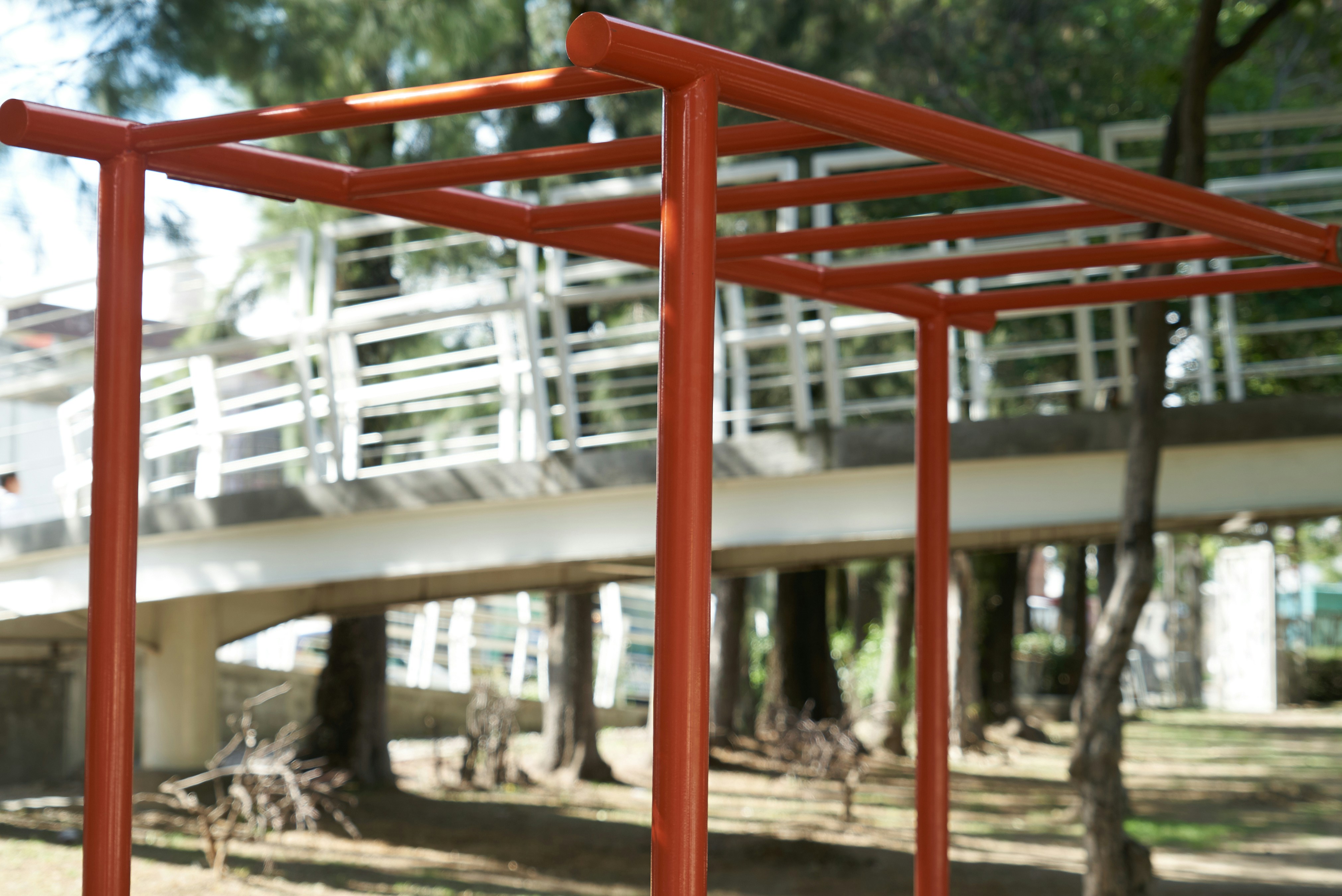 Brightly colored playground structure set against a backdrop of trees and a modern bridge. The design emphasizes the harmony between urban elements and natural surroundings.