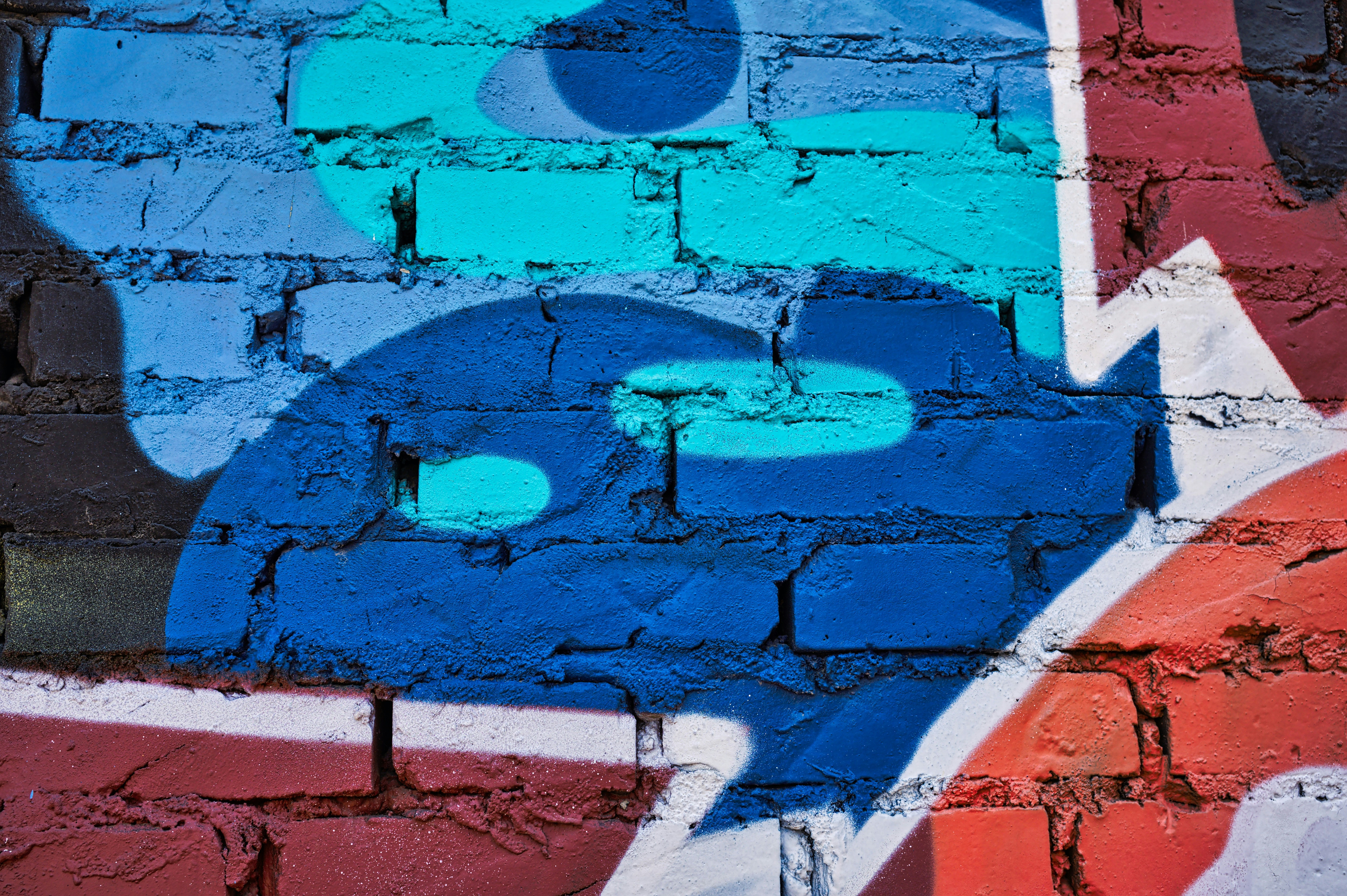 Bold abstract mural with blue and red shapes on a brick wall.