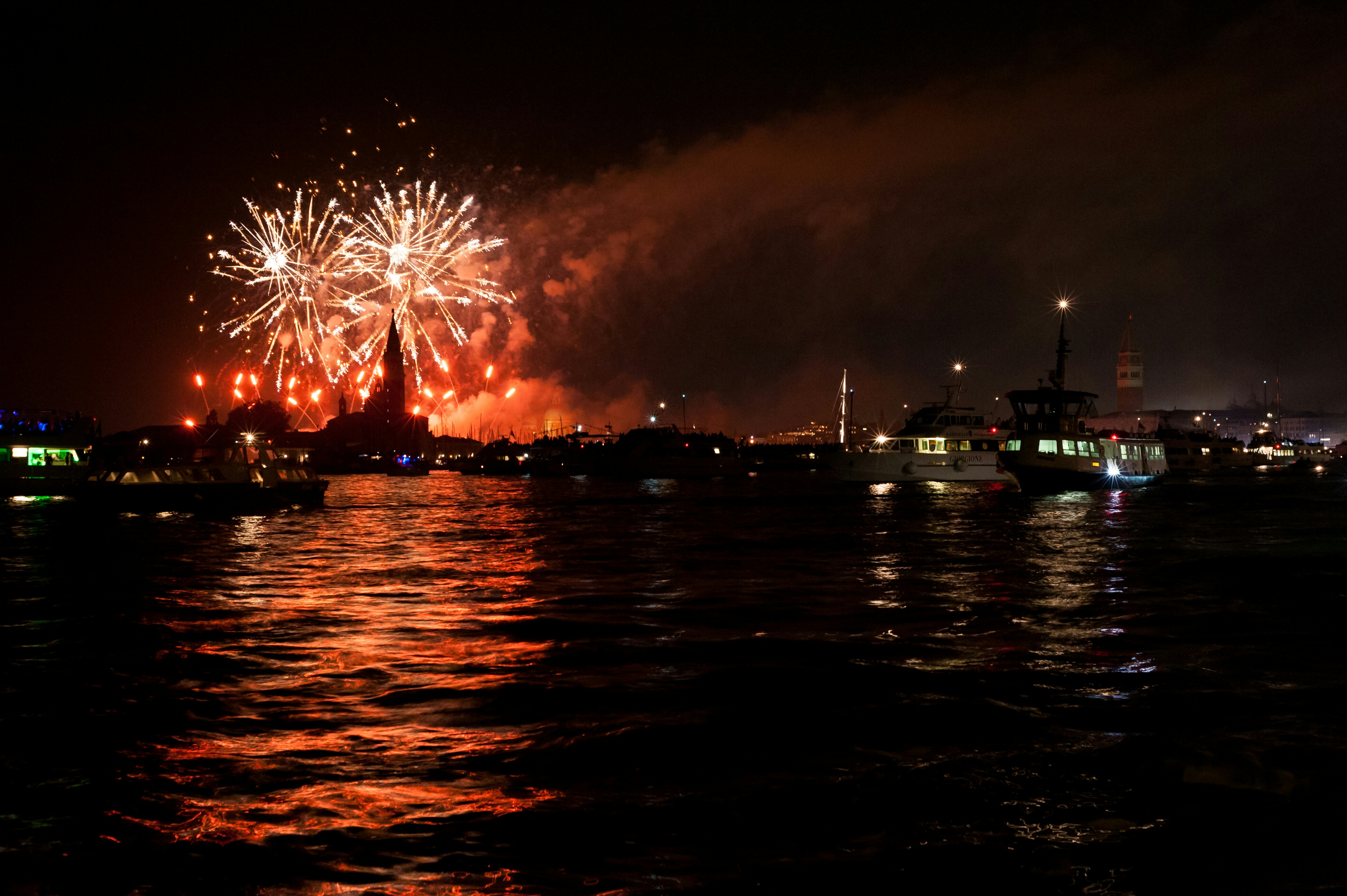 Crimson Firework Bursts Over a Night Harbor