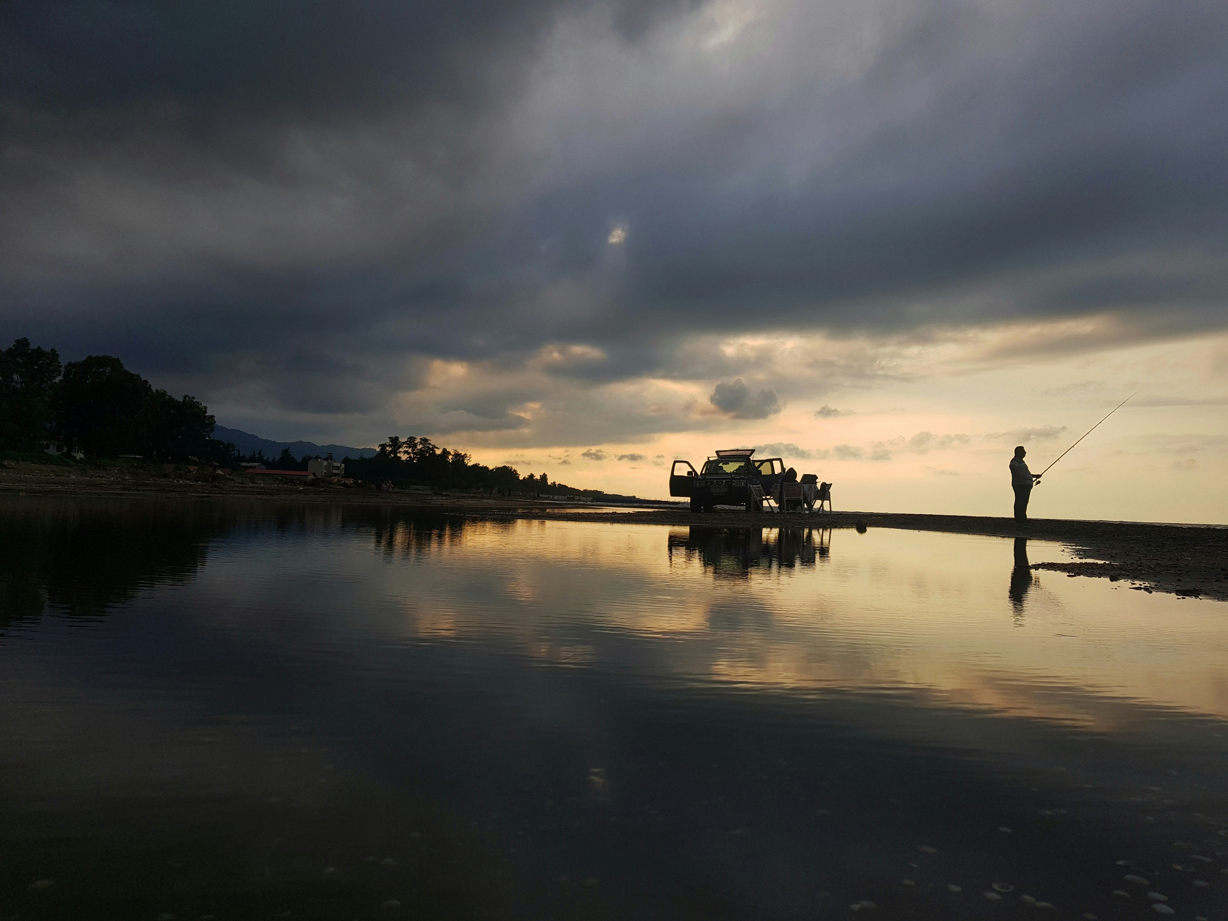 Silhouetted Fisherman at Sunset over Quiet Tidal Pool