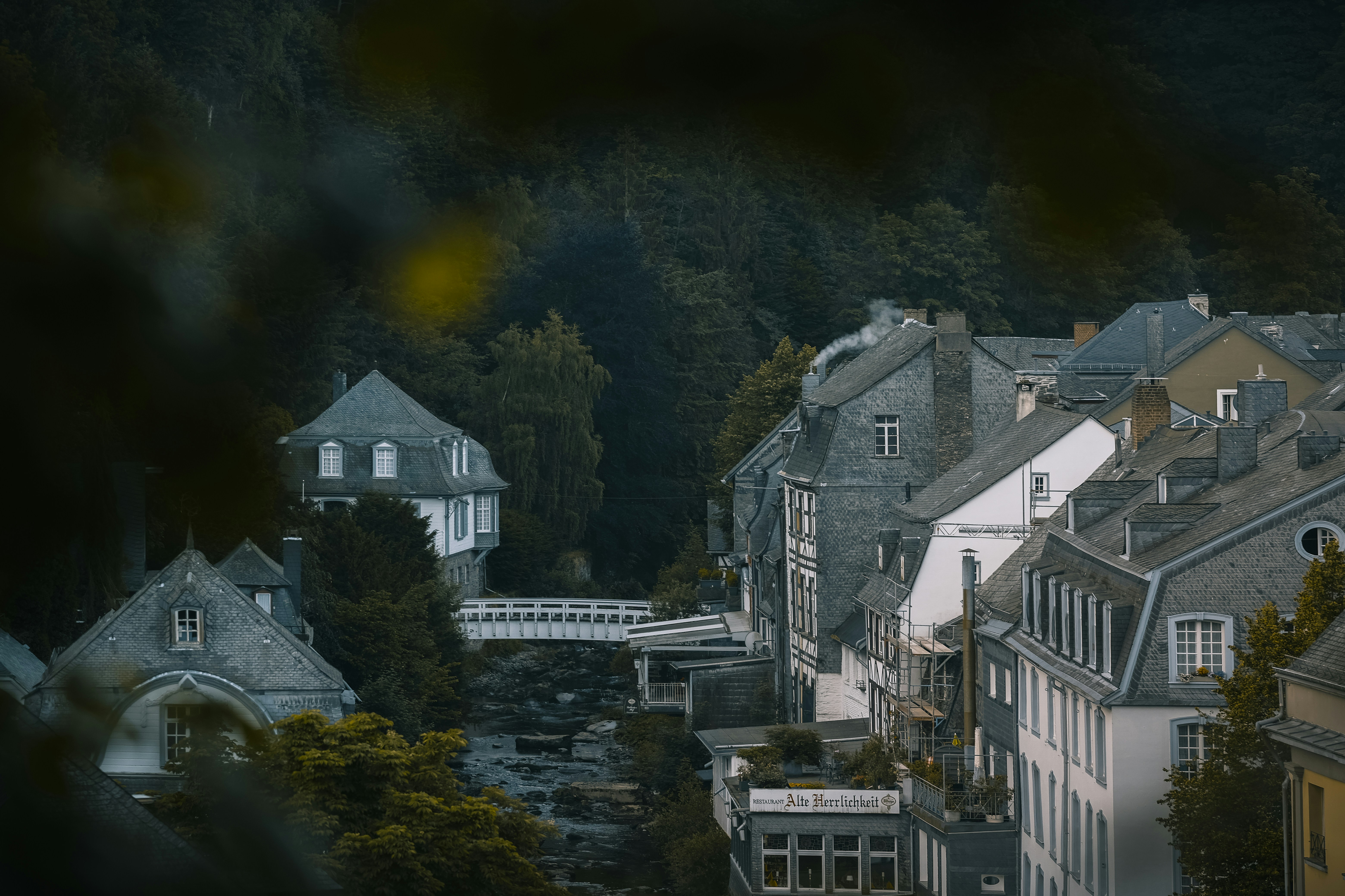Quaint village with steep-roofed houses nestled in a lush valley at dusk.