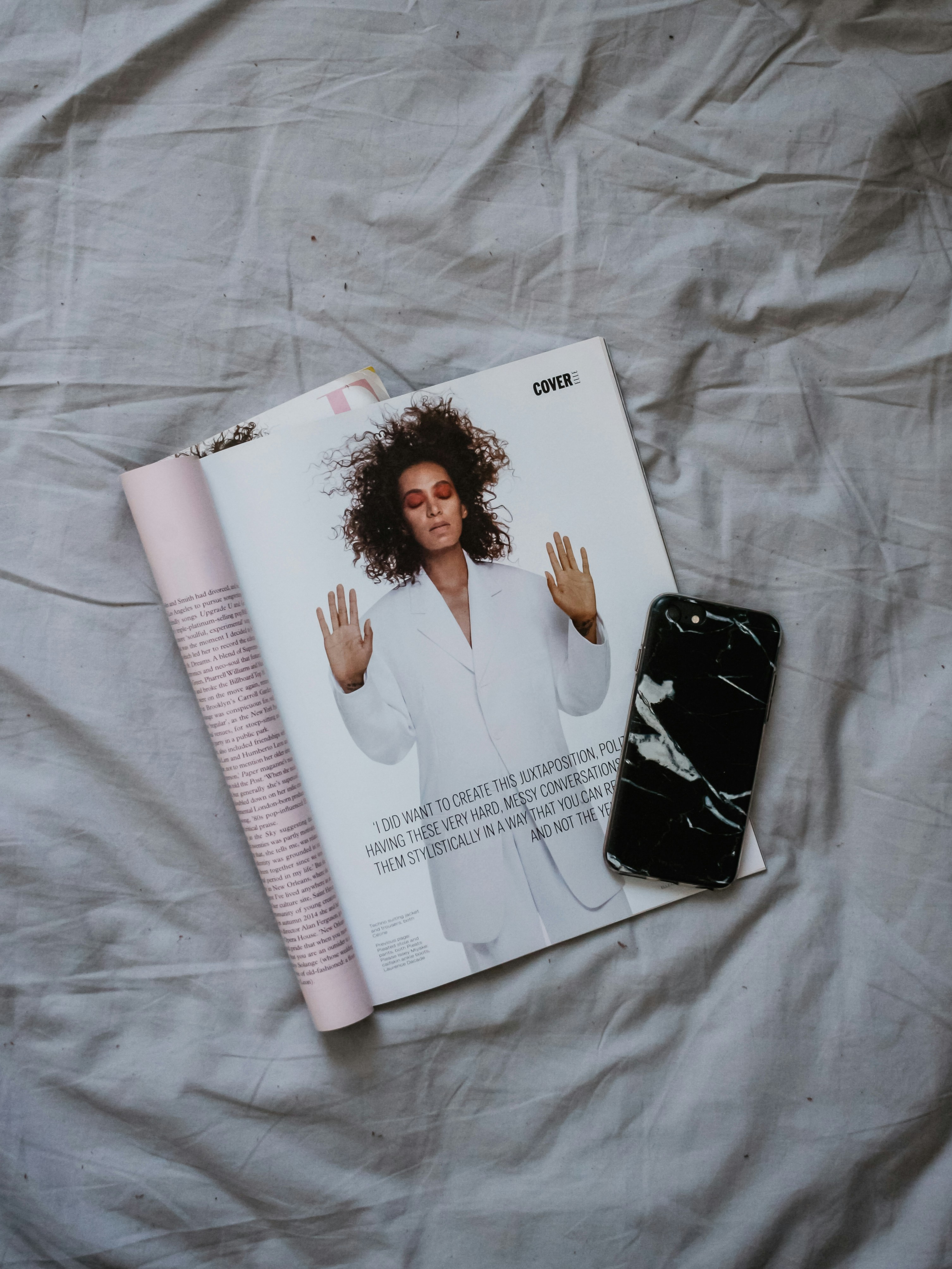White-Suited Stillness: A Fashion Magazine Portrait Framed by a Cracked Phone