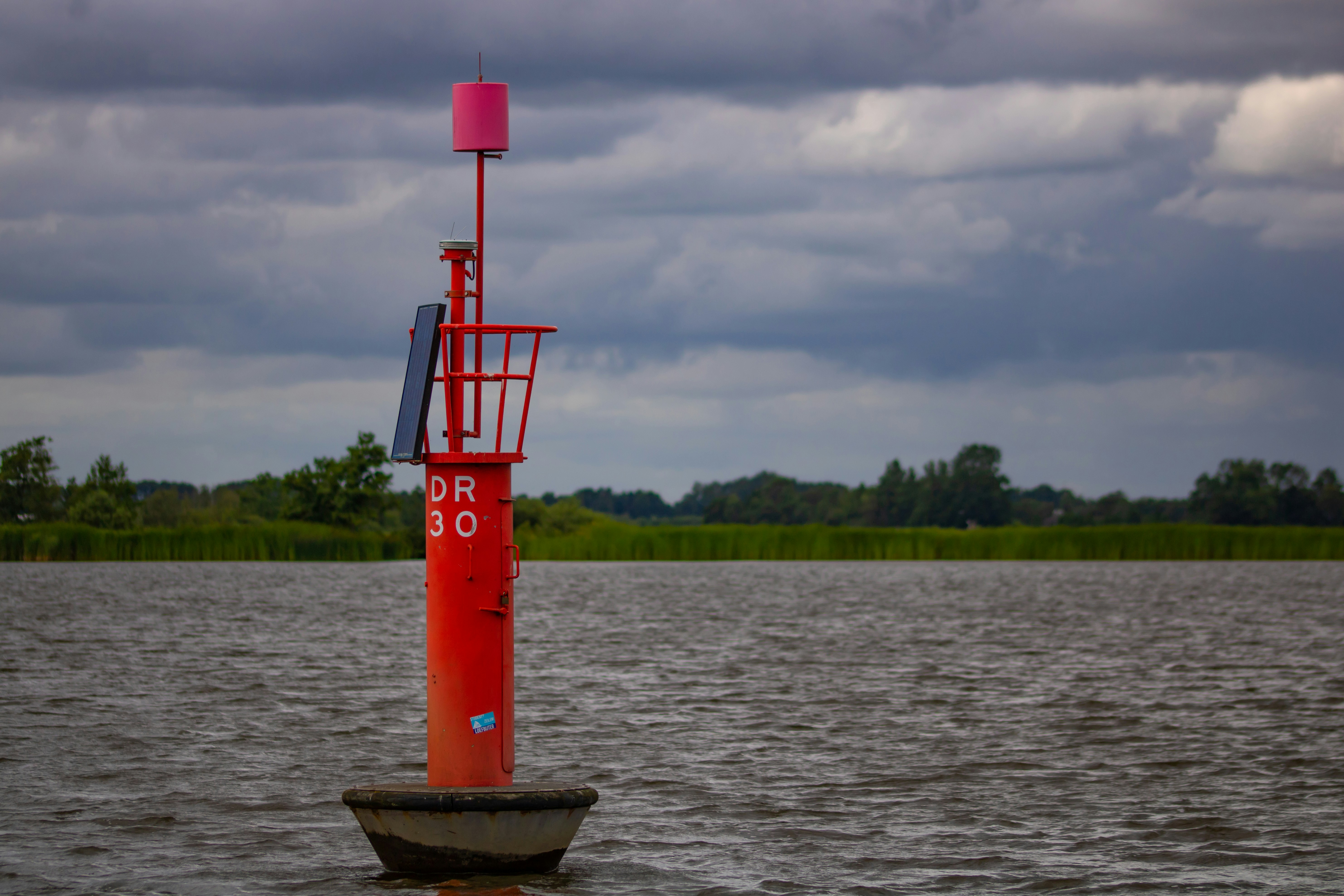 Red Sentinel on a Wide River under Overcast Skies
