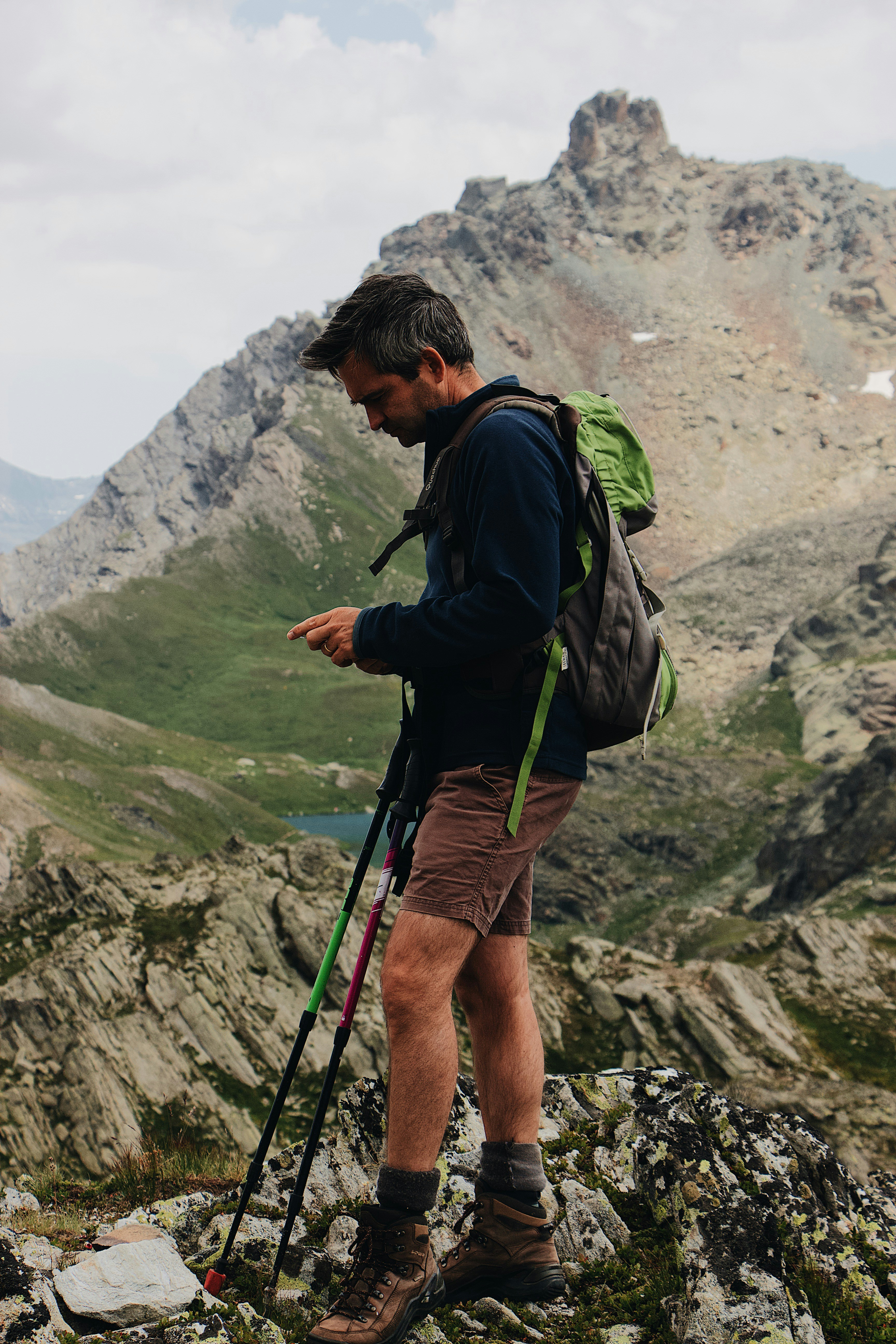 Alpine Pause: Trekker Checks the Route Above Rugged Peaks