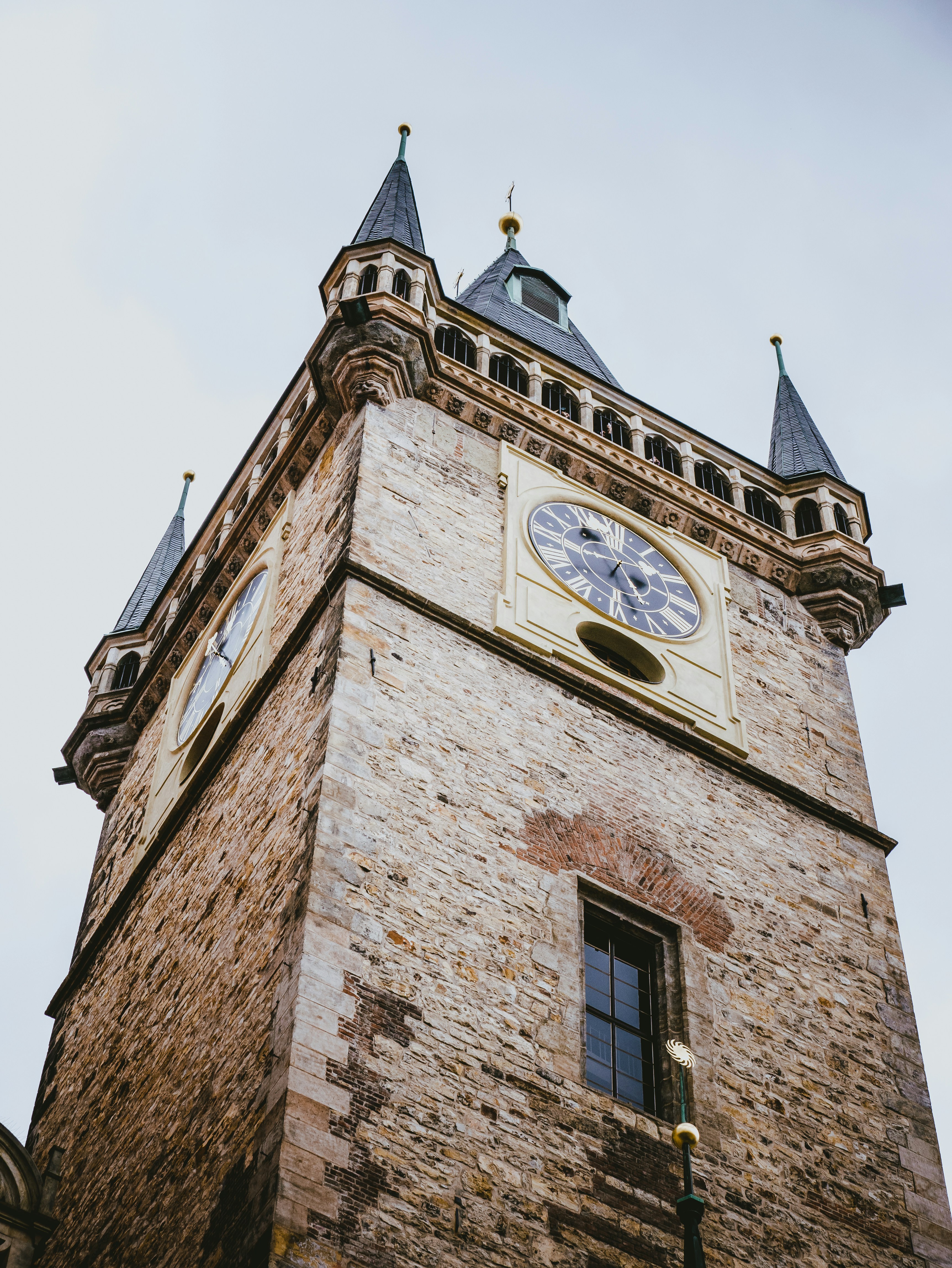 Historic clock tower with intricate stonework and spires, showcasing its grandeur against a cloudy sky.