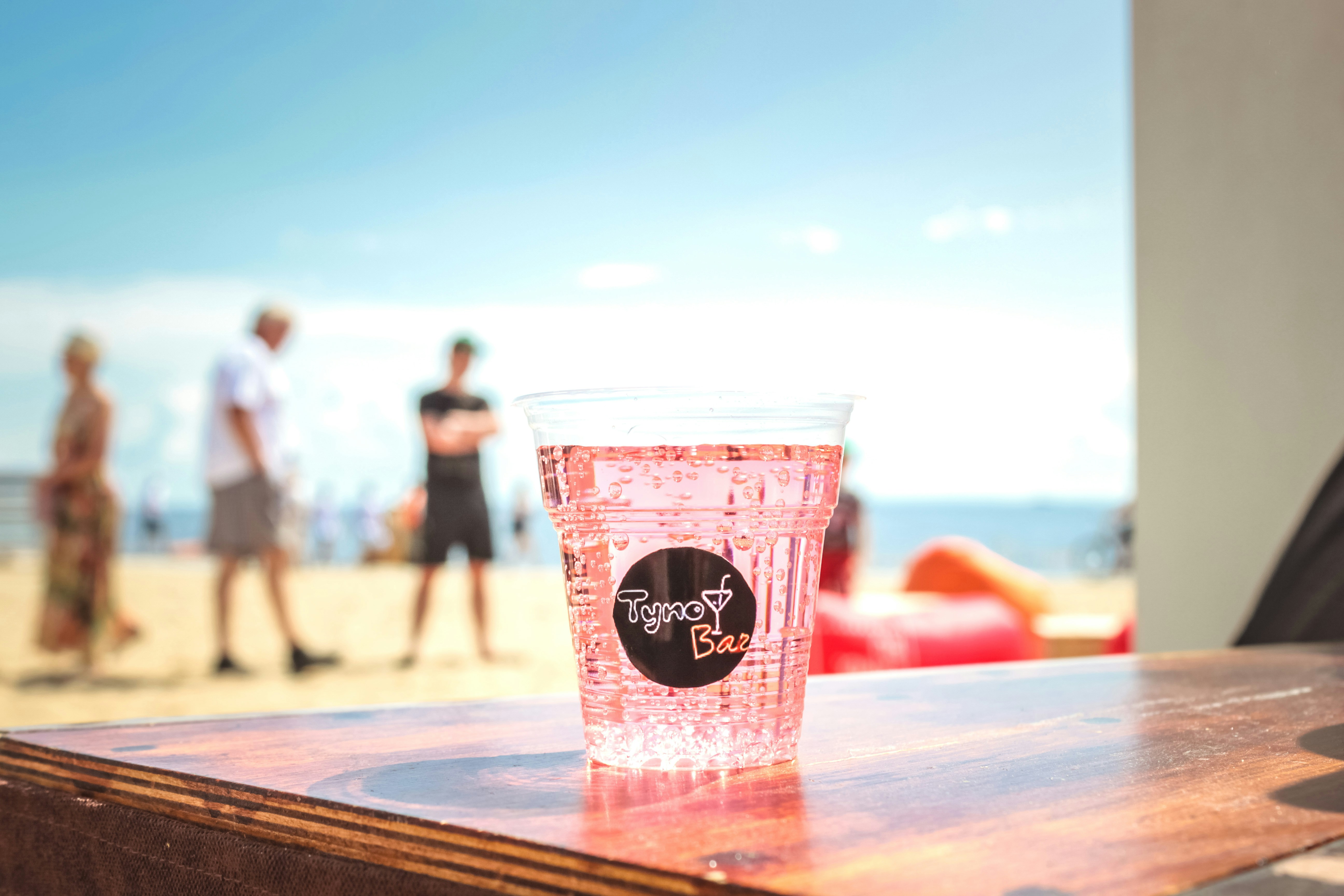 Sunlit Pink Sip: A Focused Moment on the Beachfront Table