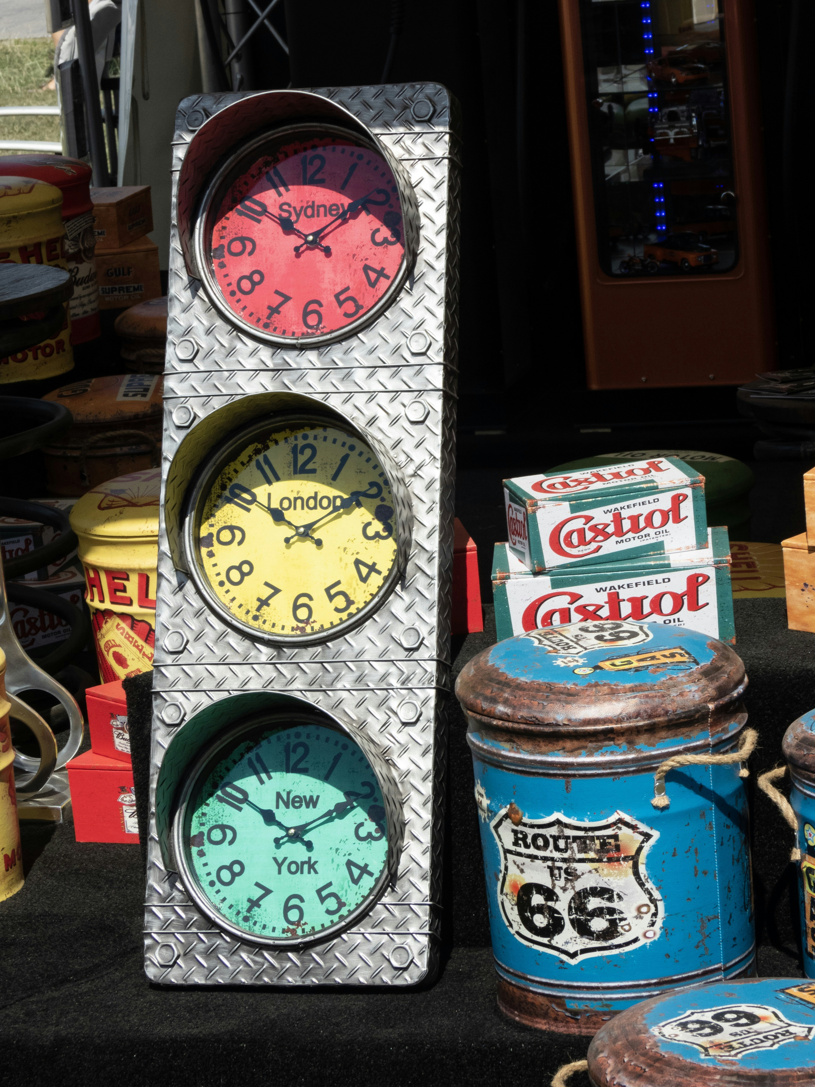 Vintage clock display featuring time zones for Sydney, London, and New York, surrounded by colorful retro cans and memorabilia.