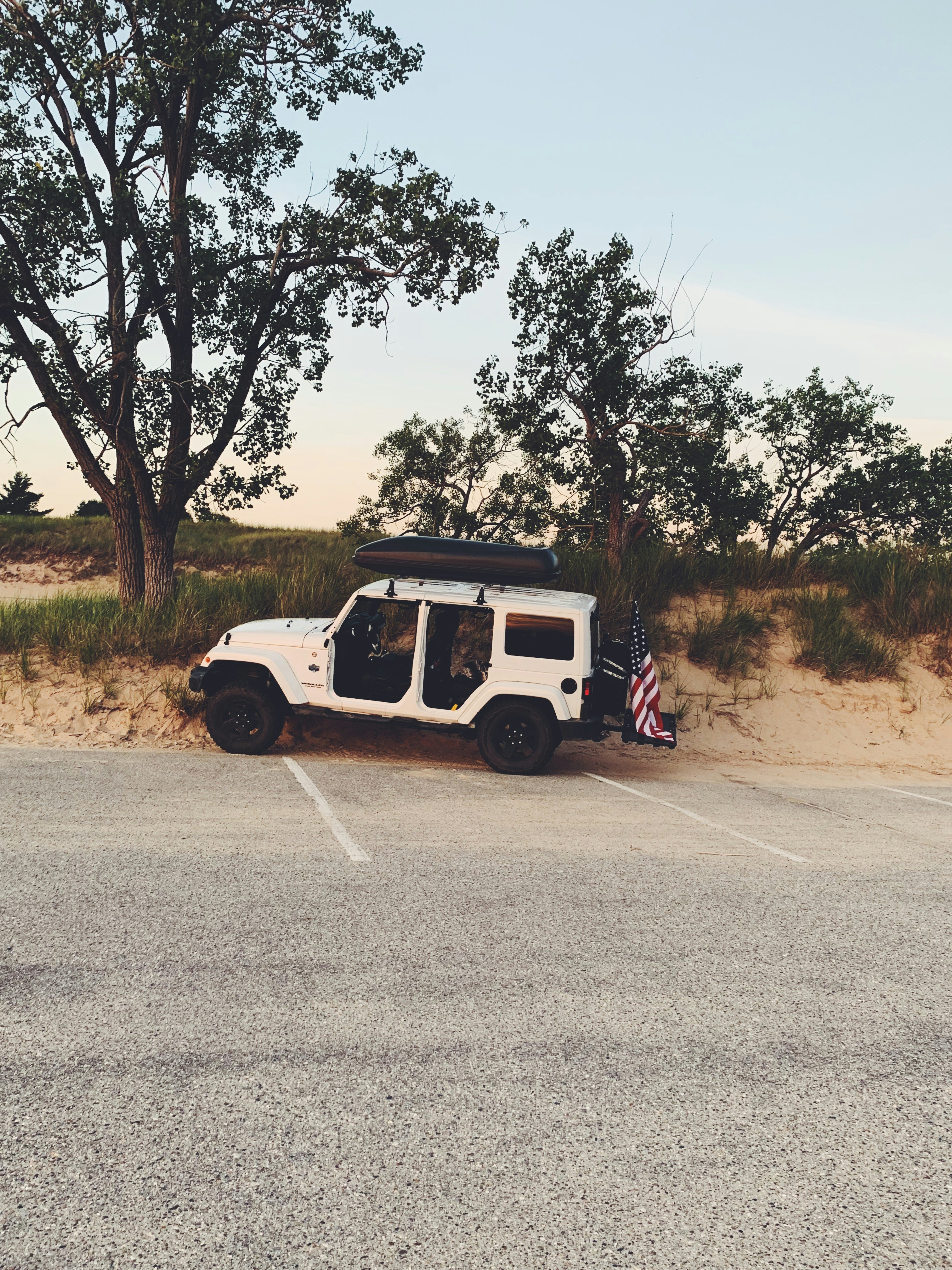 Flag-Waved Jeep Wrangler by a Dune-Edge Parking Lot