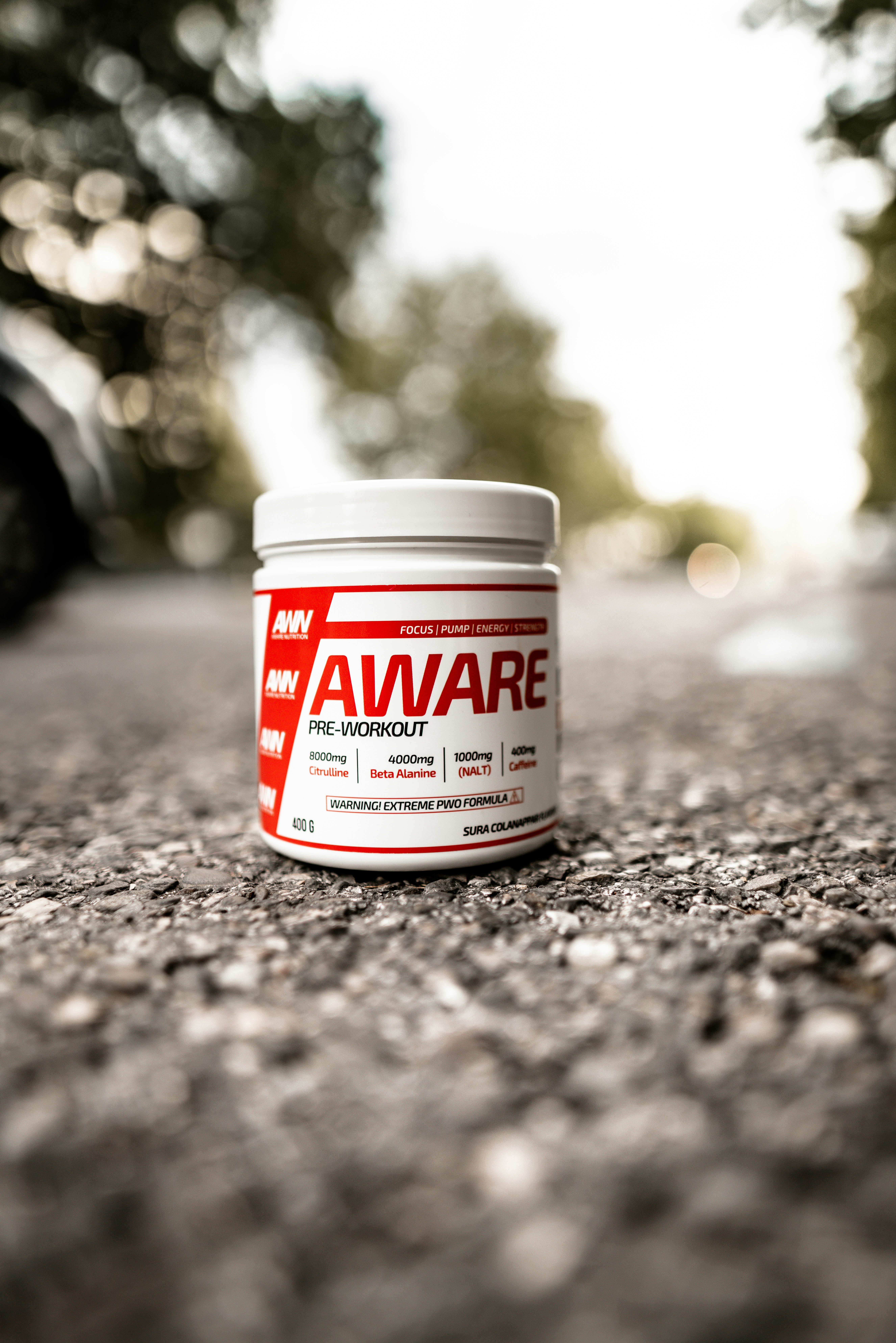 Ground-Level Spotlight: AWARE Pre-Workout Jar on Sunlit Asphalt