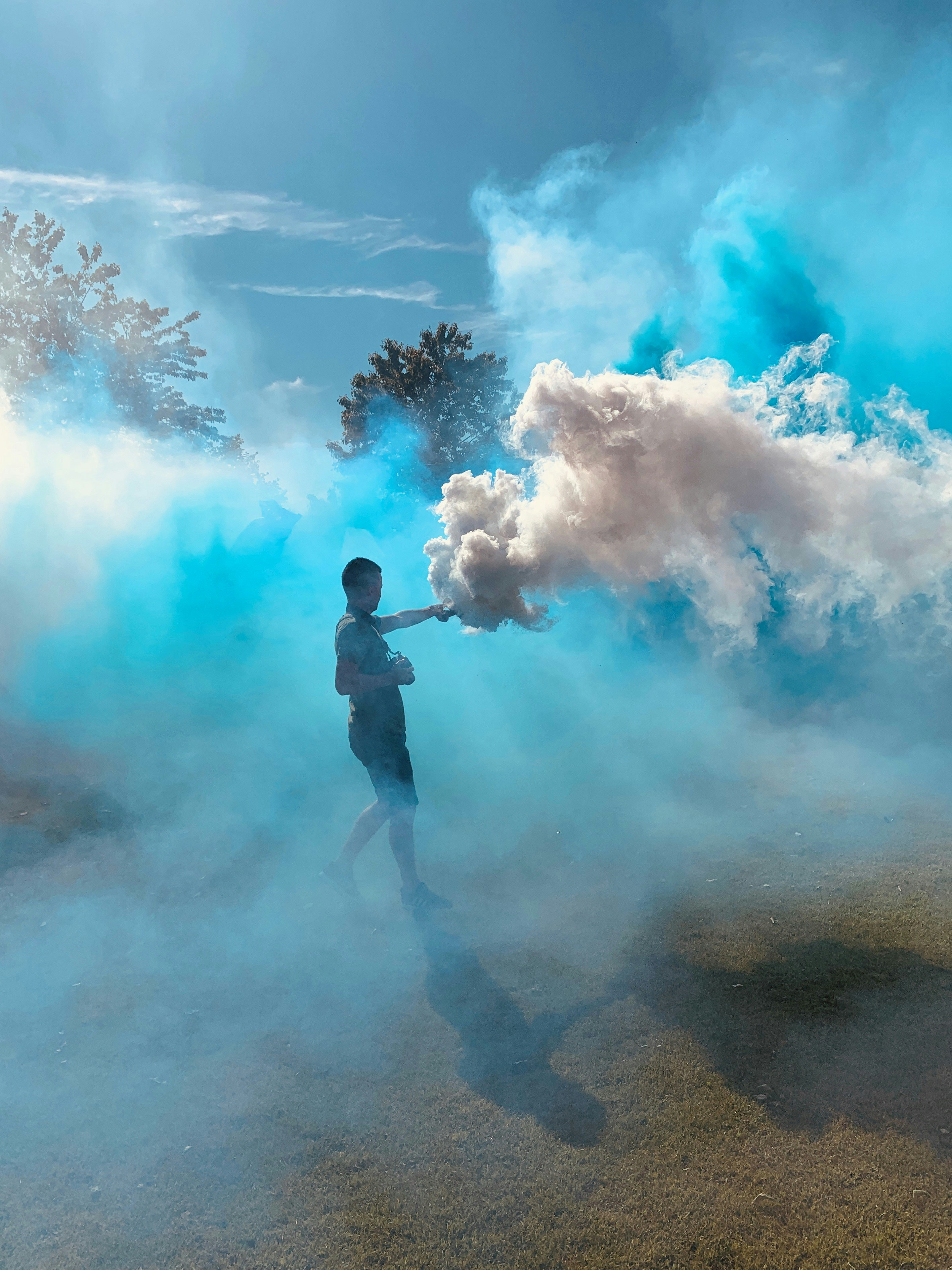 Cyan Cloudscape: A Child Unleashing Blue Smoke in an Open Field