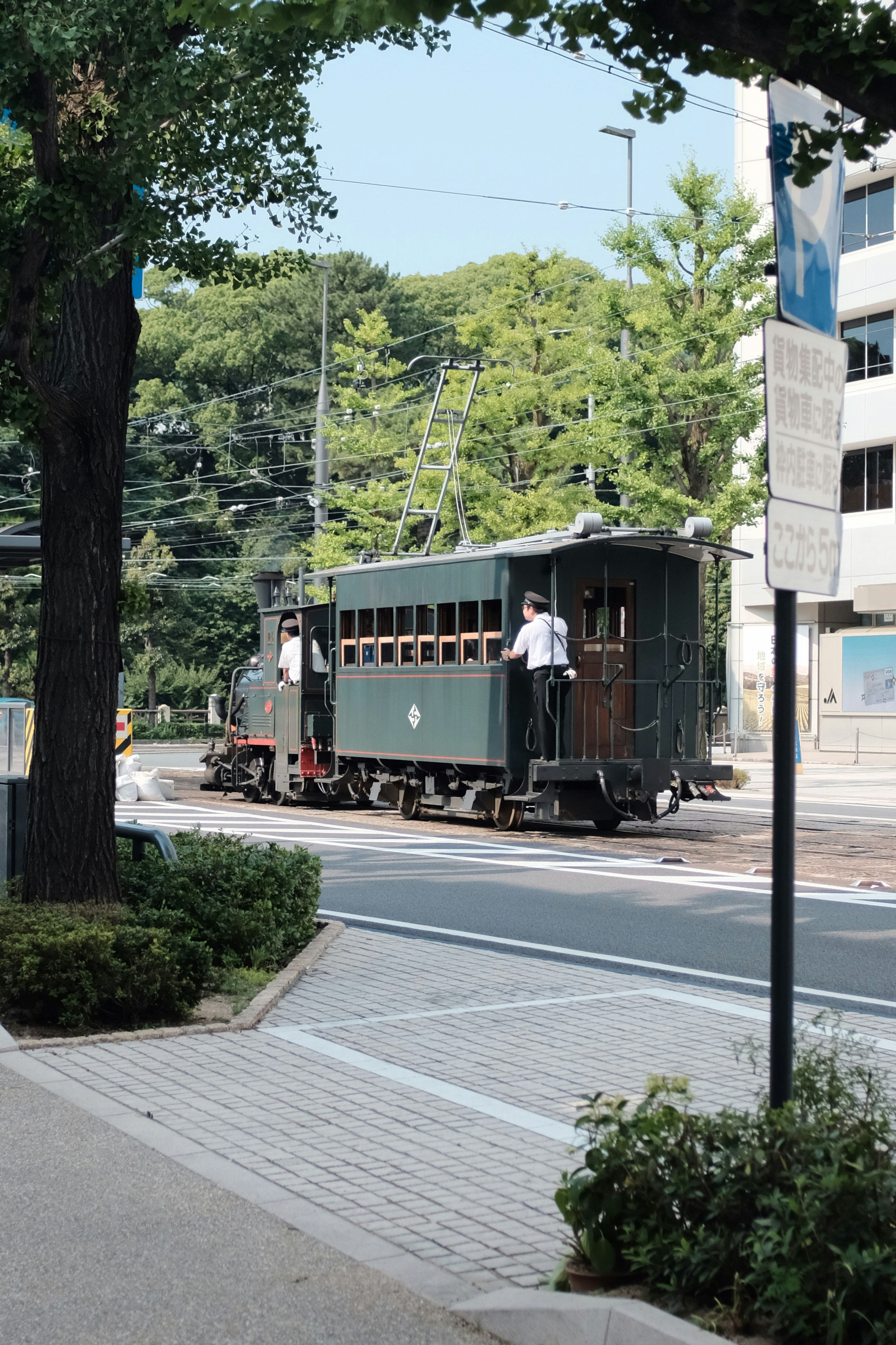 Vintage tram navigating through a bustling city street, flanked by lush greenery and modern architecture.
