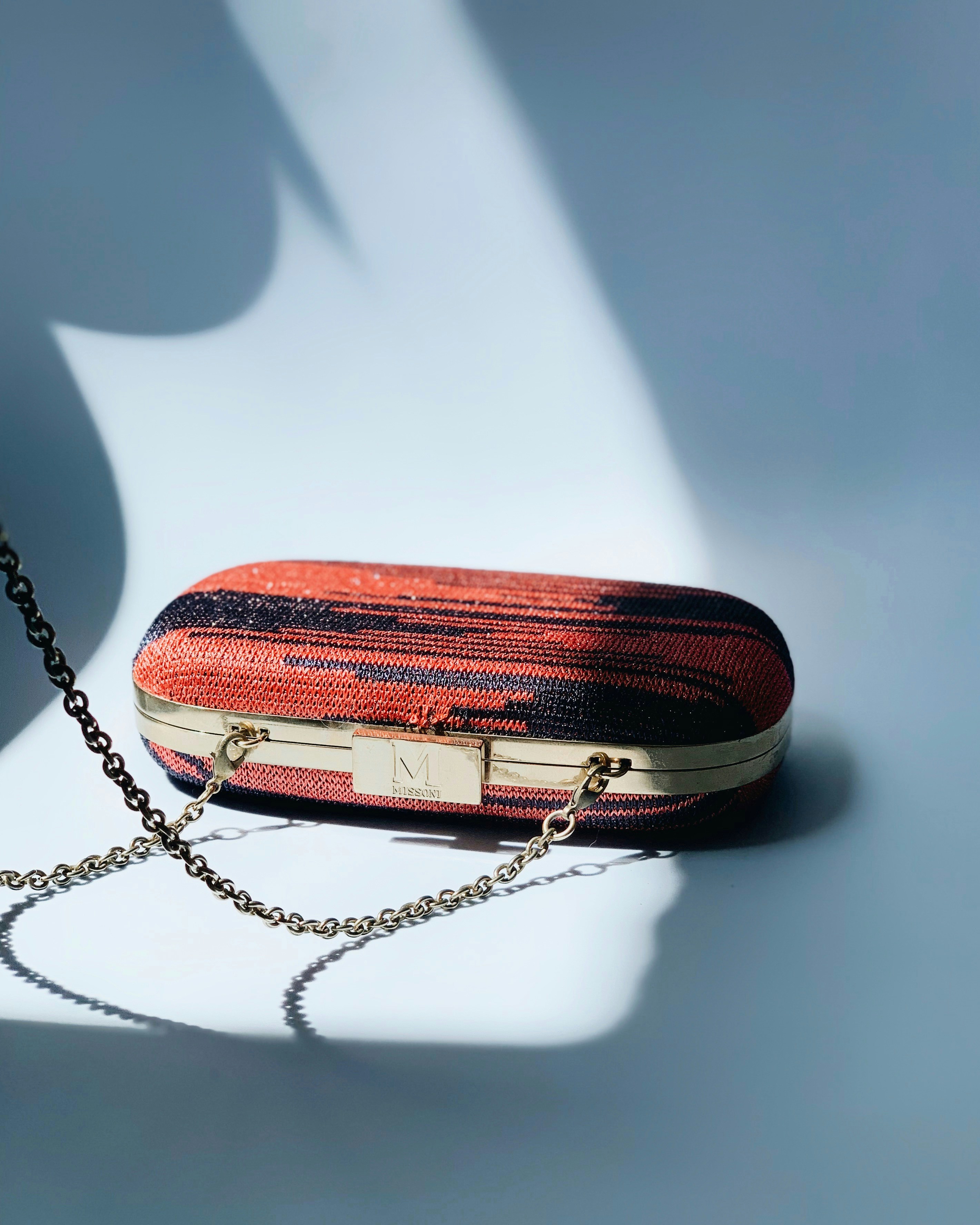 Stripe-and-Gold: A Red-Black Clutch Resting in Soft Studio Light