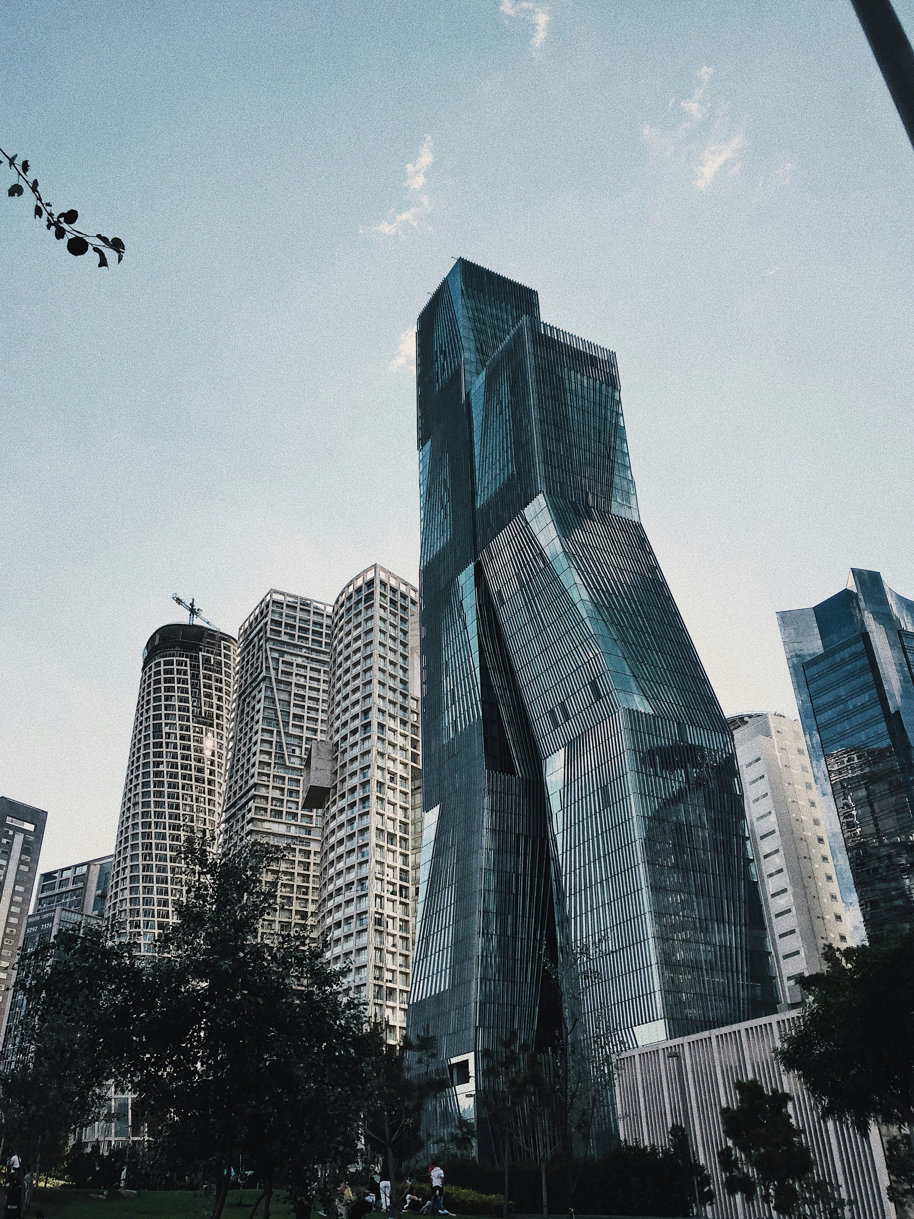 Modern skyscrapers with angular designs rise against a clear blue sky.
