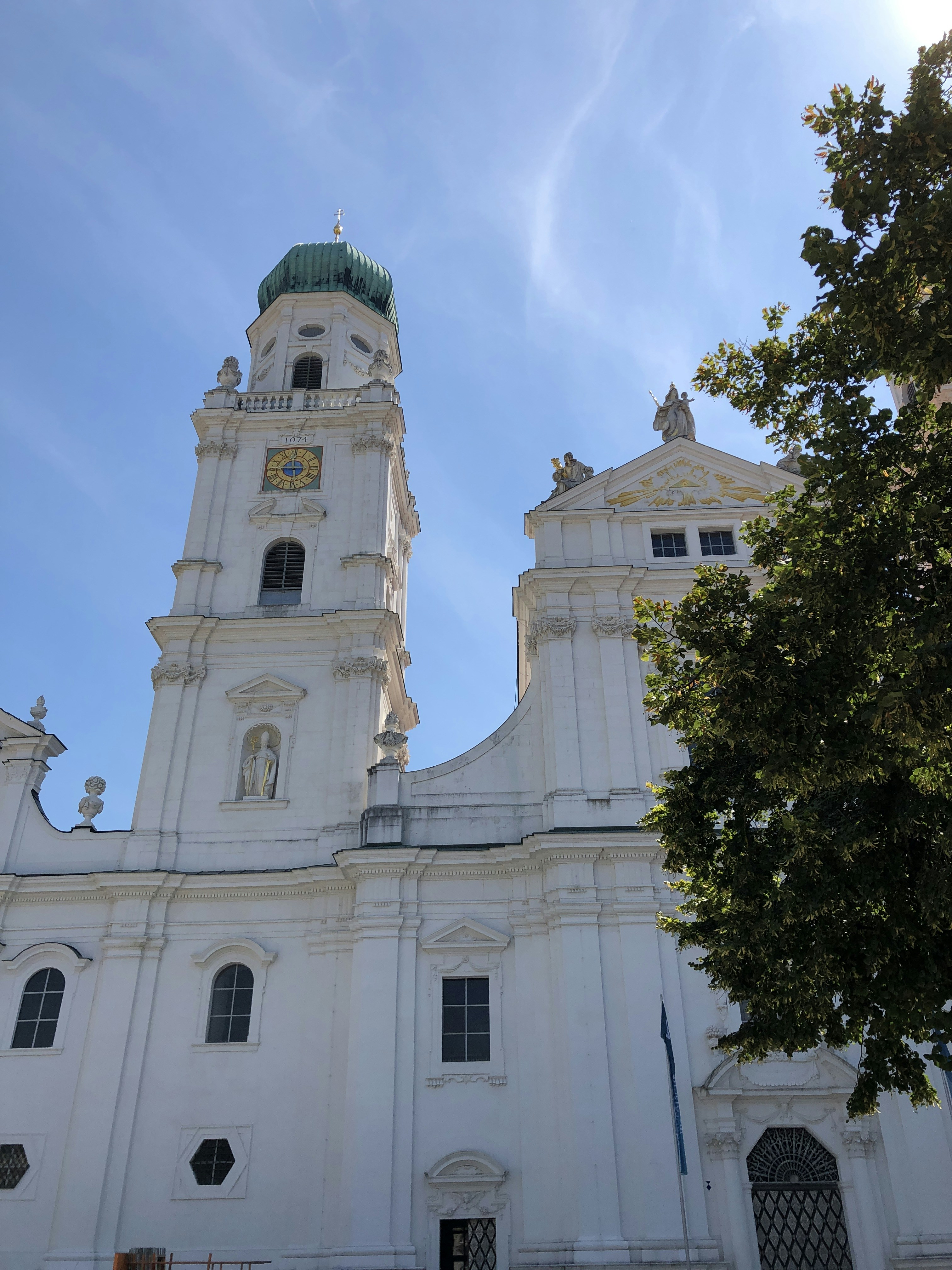 Baroque church facade showcasing intricate details and a striking clock tower under a clear blue sky.