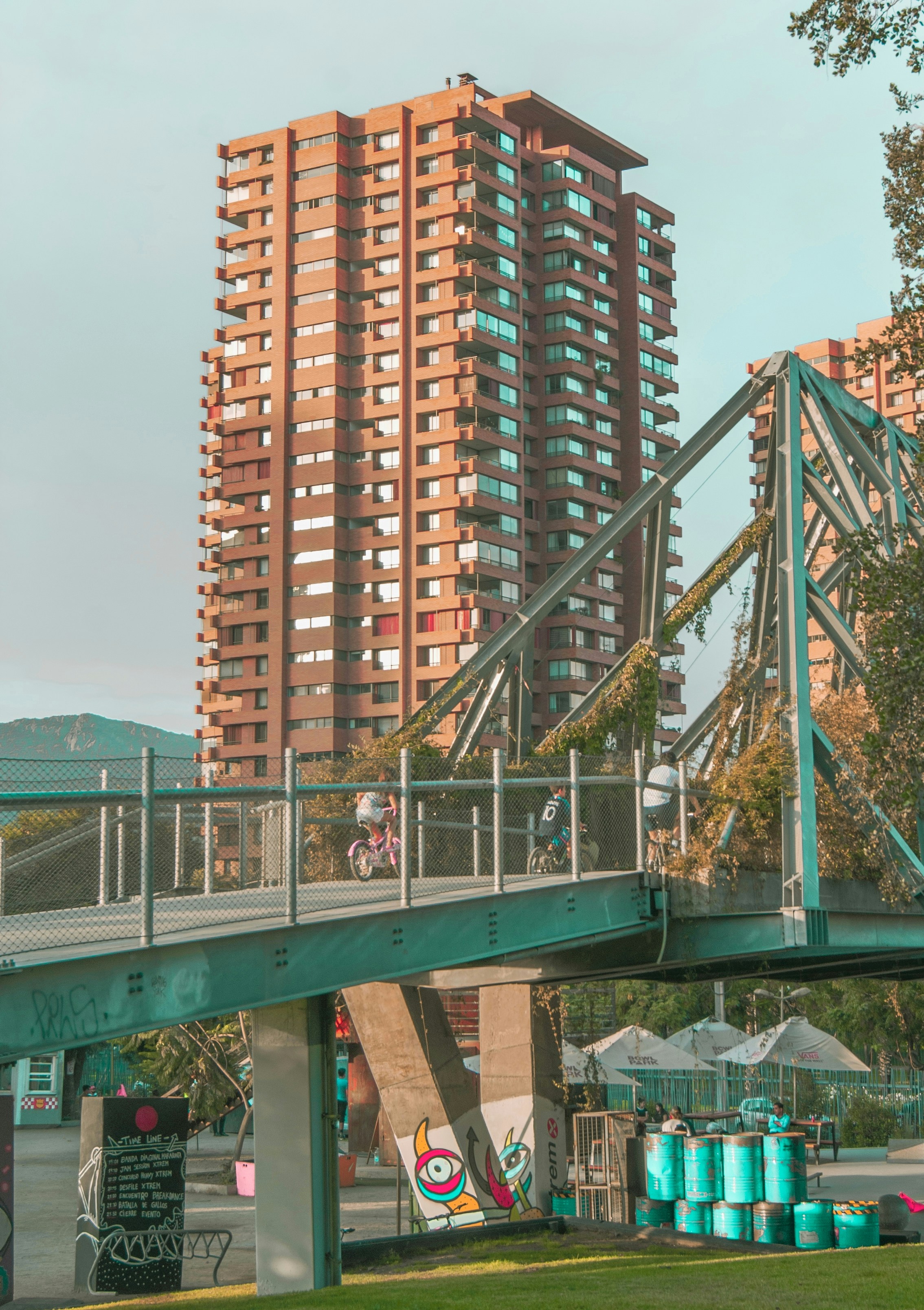 Pedestrian bridge with modern high-rise buildings in the background under a clear sky.