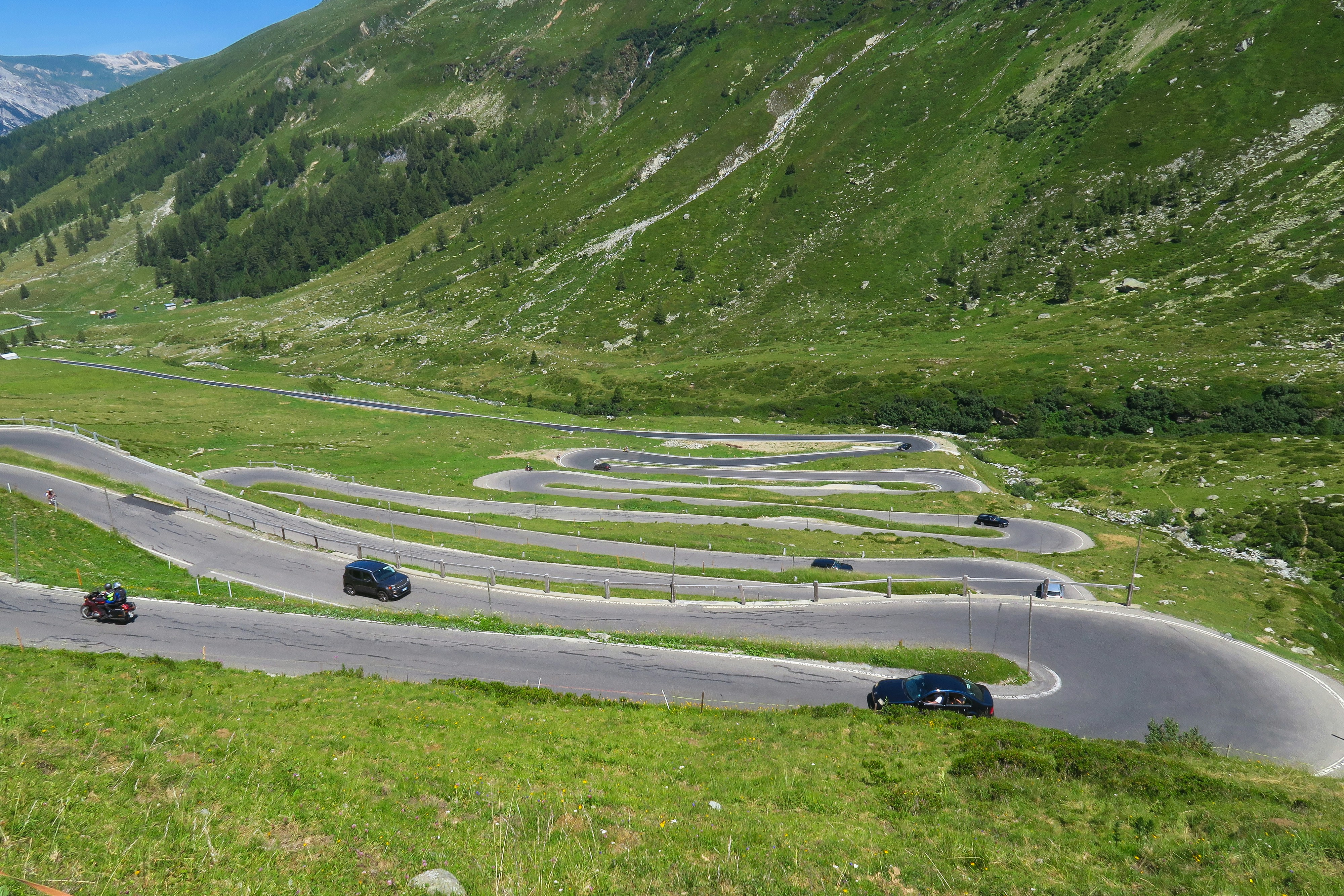 Splugenpass - Switzerland | photography of vehicles traveling on road near mountain during daytime
