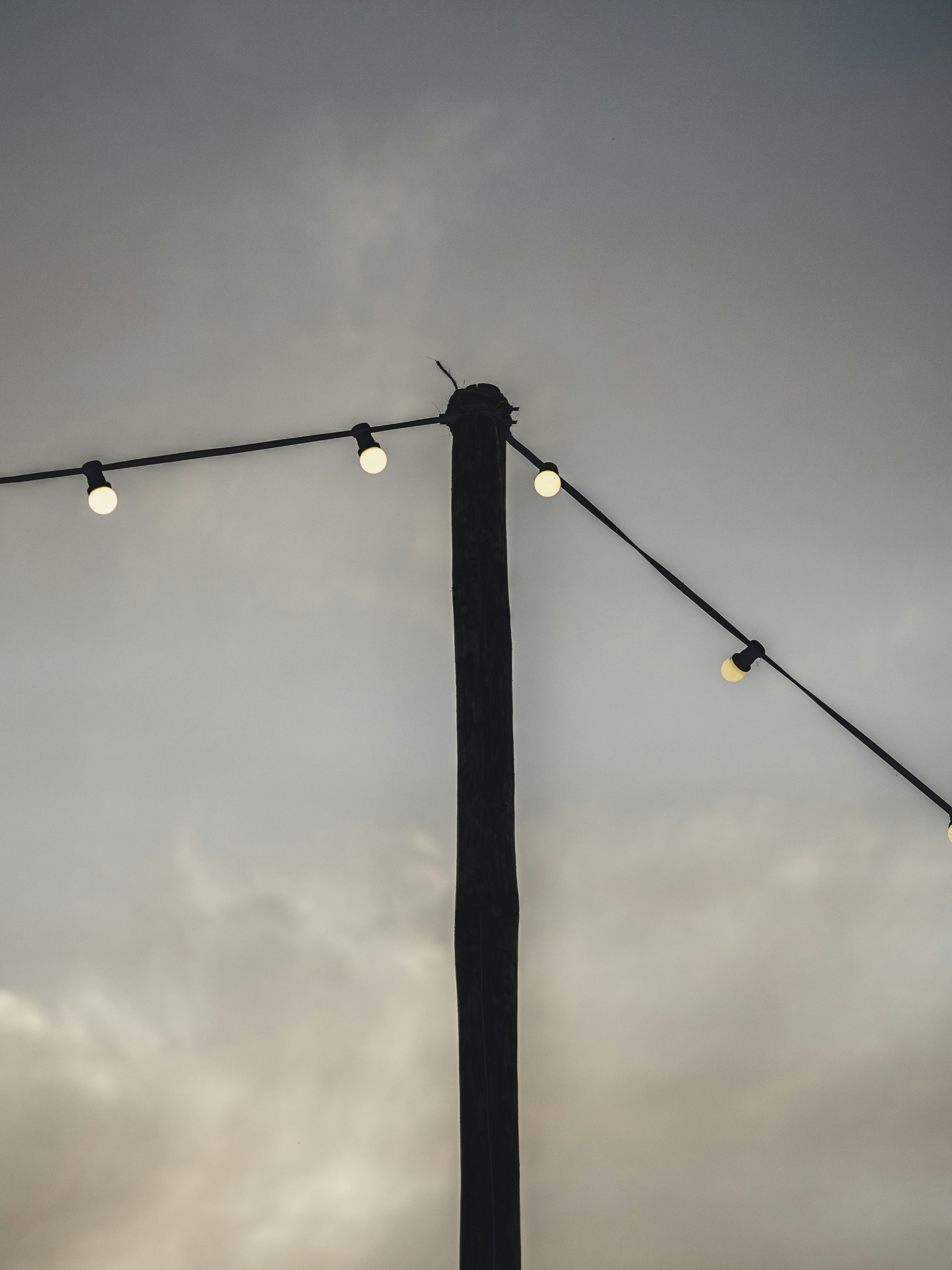 Pole of Light: A Minimal String of Bulbs Against a Cloudy Sky