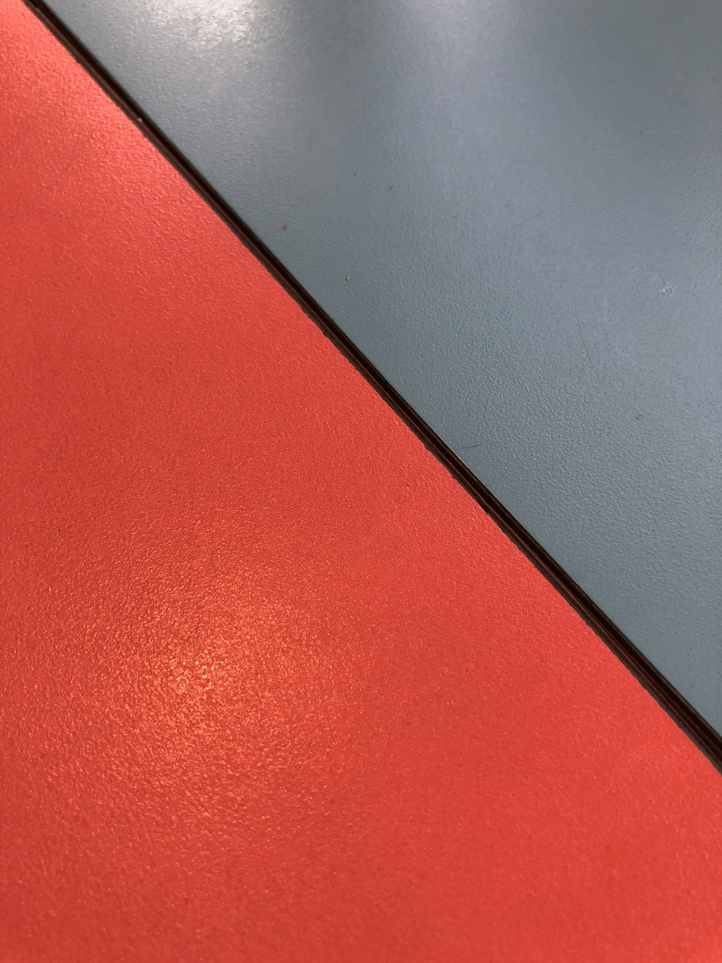 Diagonal division of a vibrant red and calming blue surface, showcasing contrasting textures and colors.
