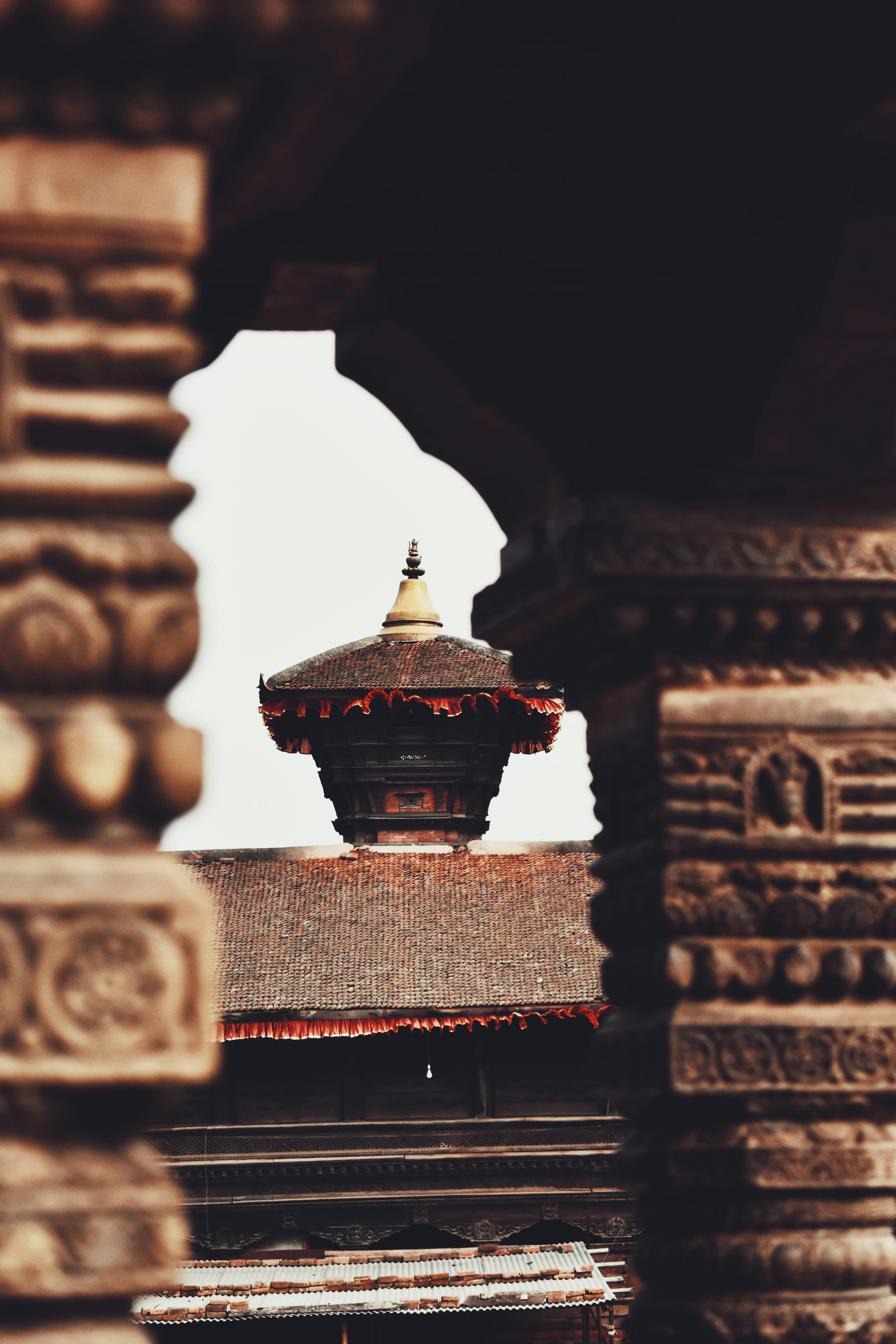 Intricate wooden carvings frame a traditional pagoda, highlighting the craftsmanship of ancient architecture. The scene captures a moment of cultural significance.