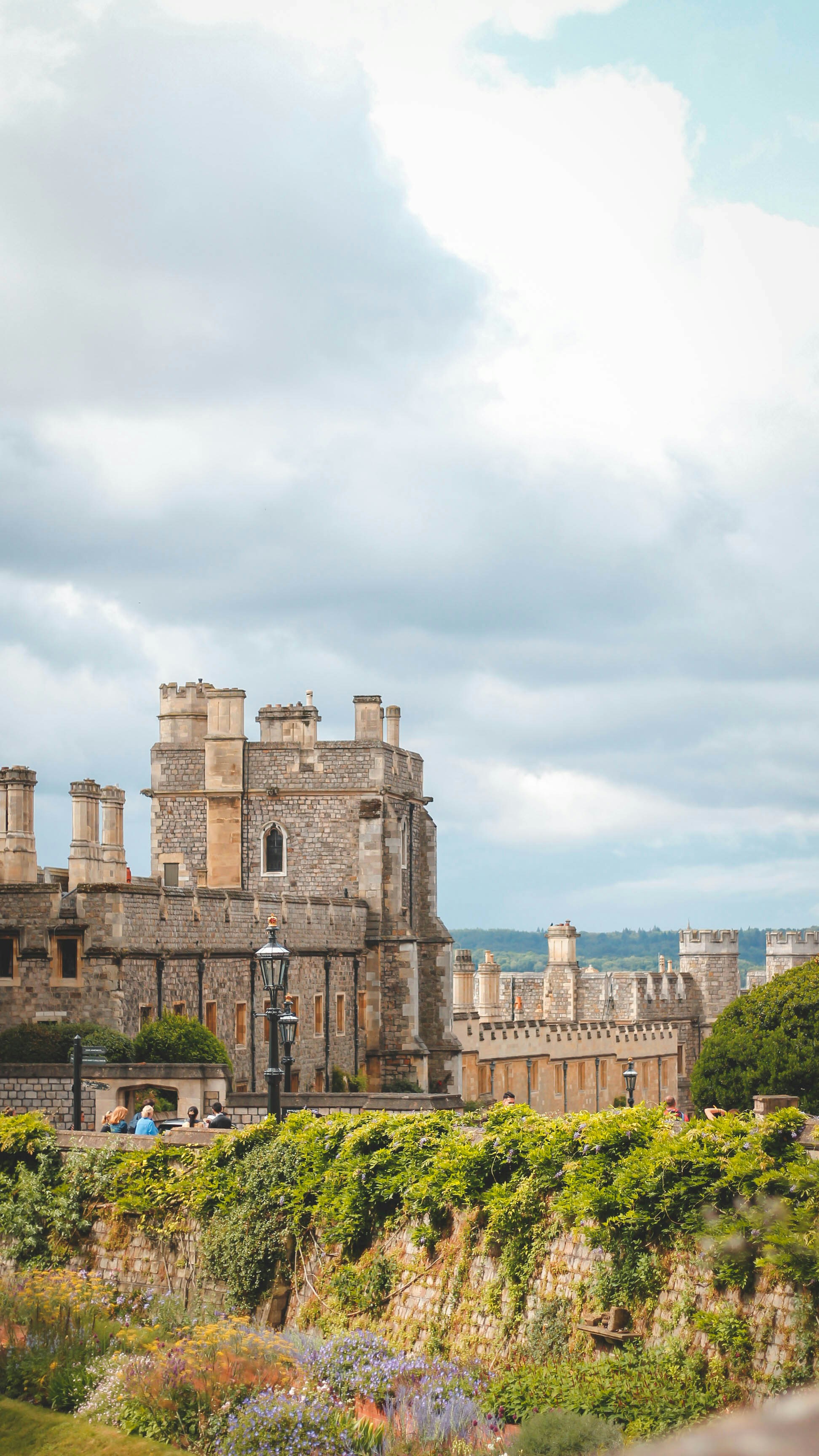Historic castle architecture framed by lush greenery and vibrant flowers, inviting visitors to explore its storied past.