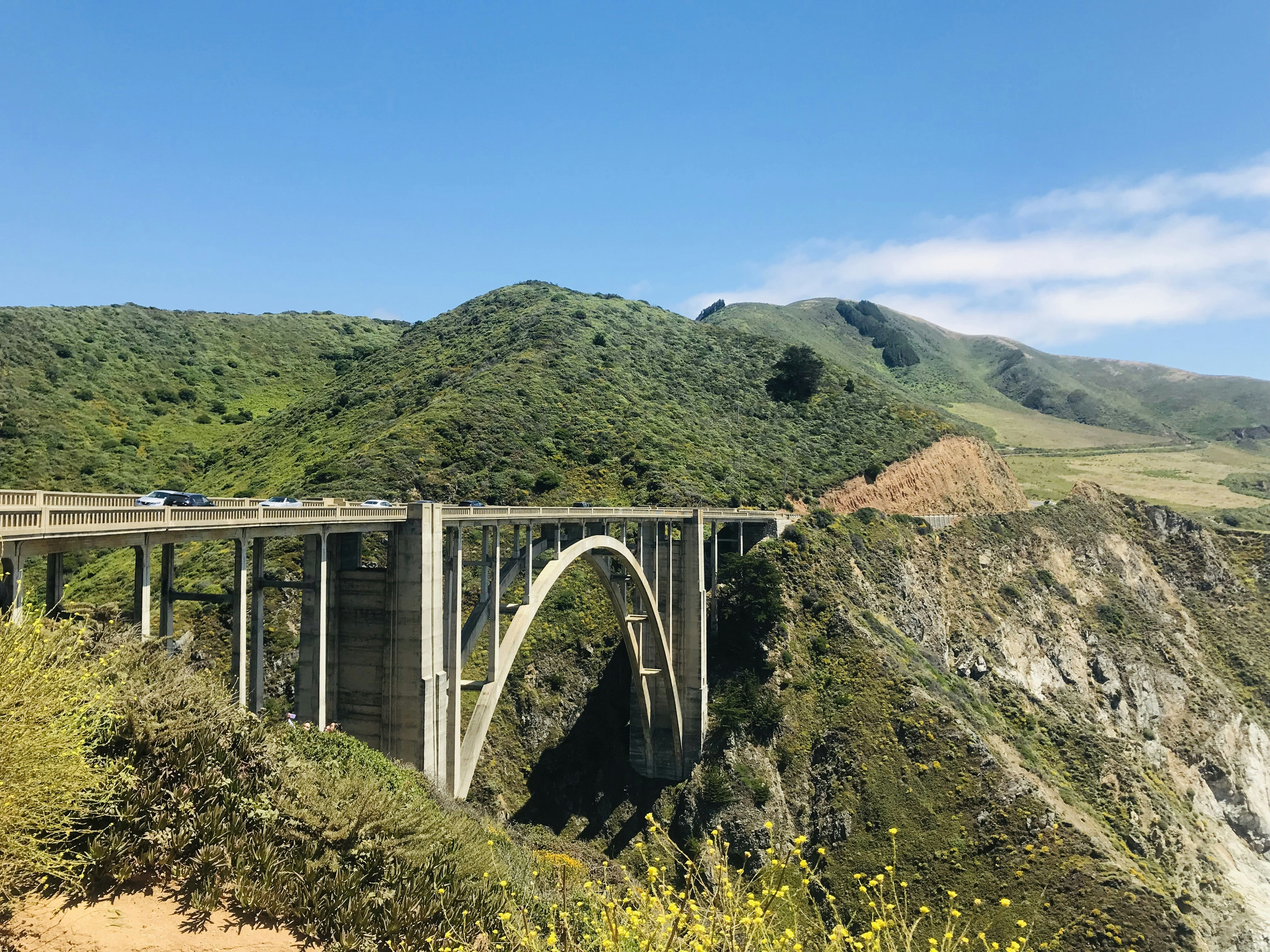 Concrete Ribbon Across a Green Gorge Under a Wide Blue Sky