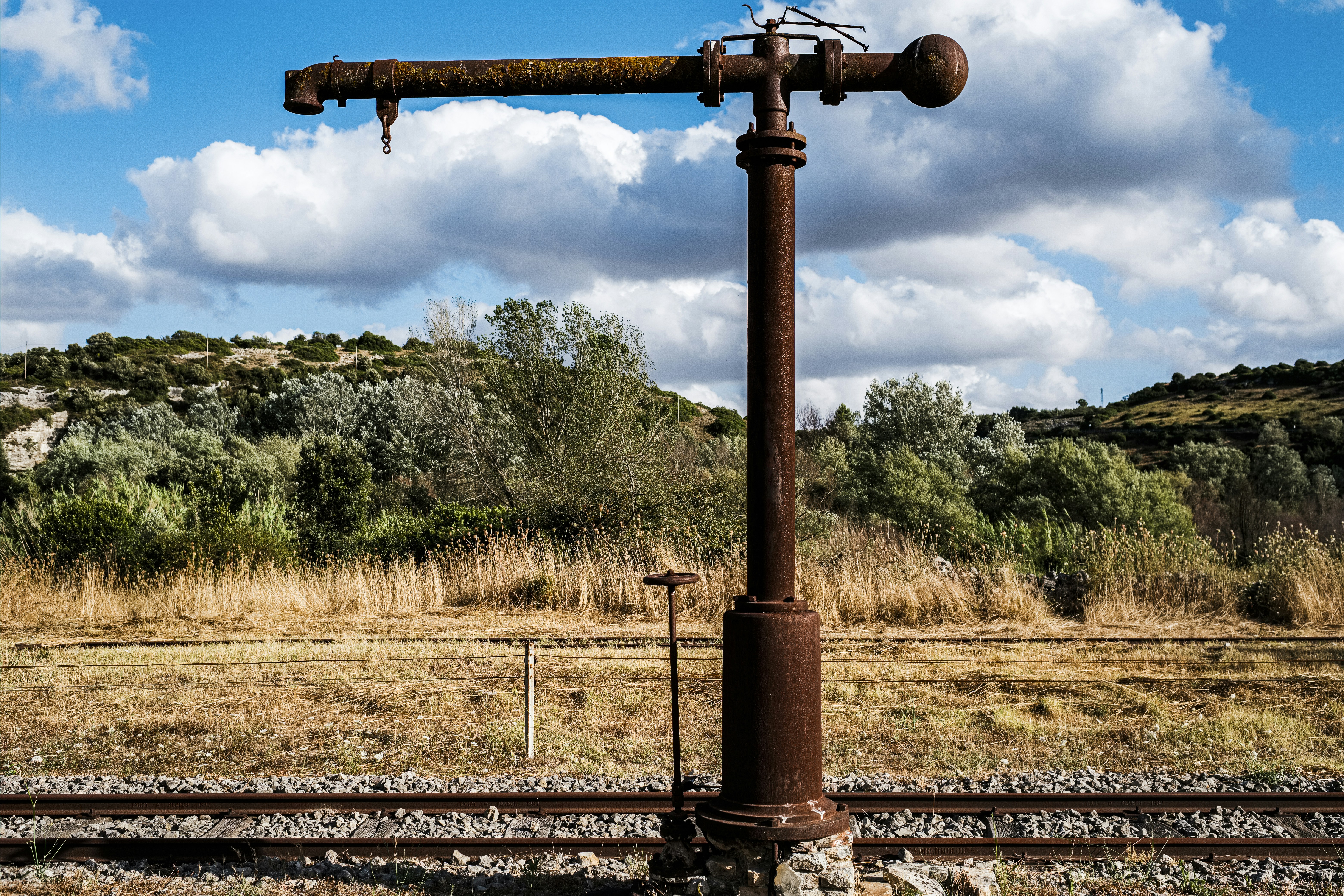 Iron Sentinel on the Rails: Water Crane Beneath a Wide Desert Sky