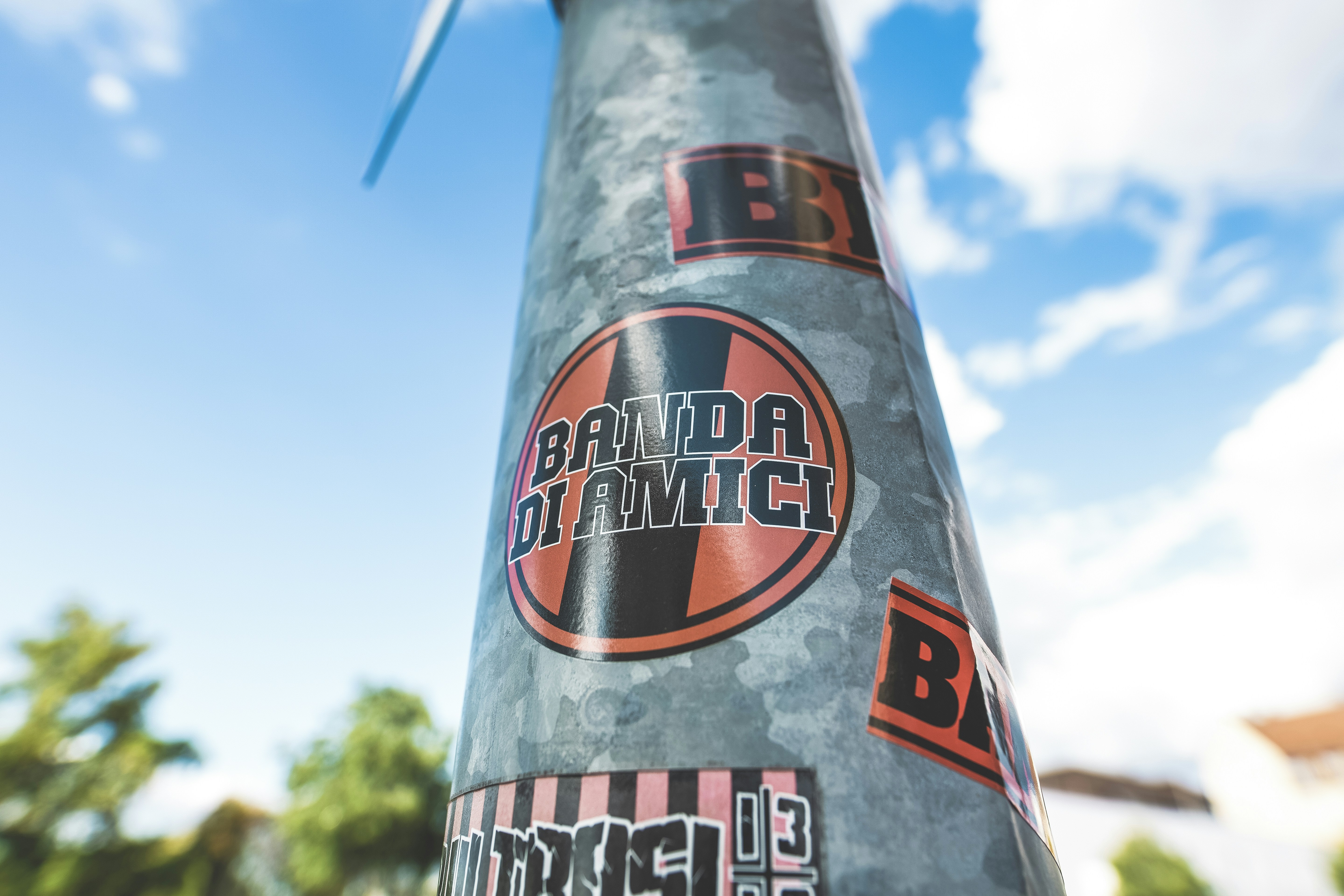 Stenciled sticker on a weathered pole rises toward the sky