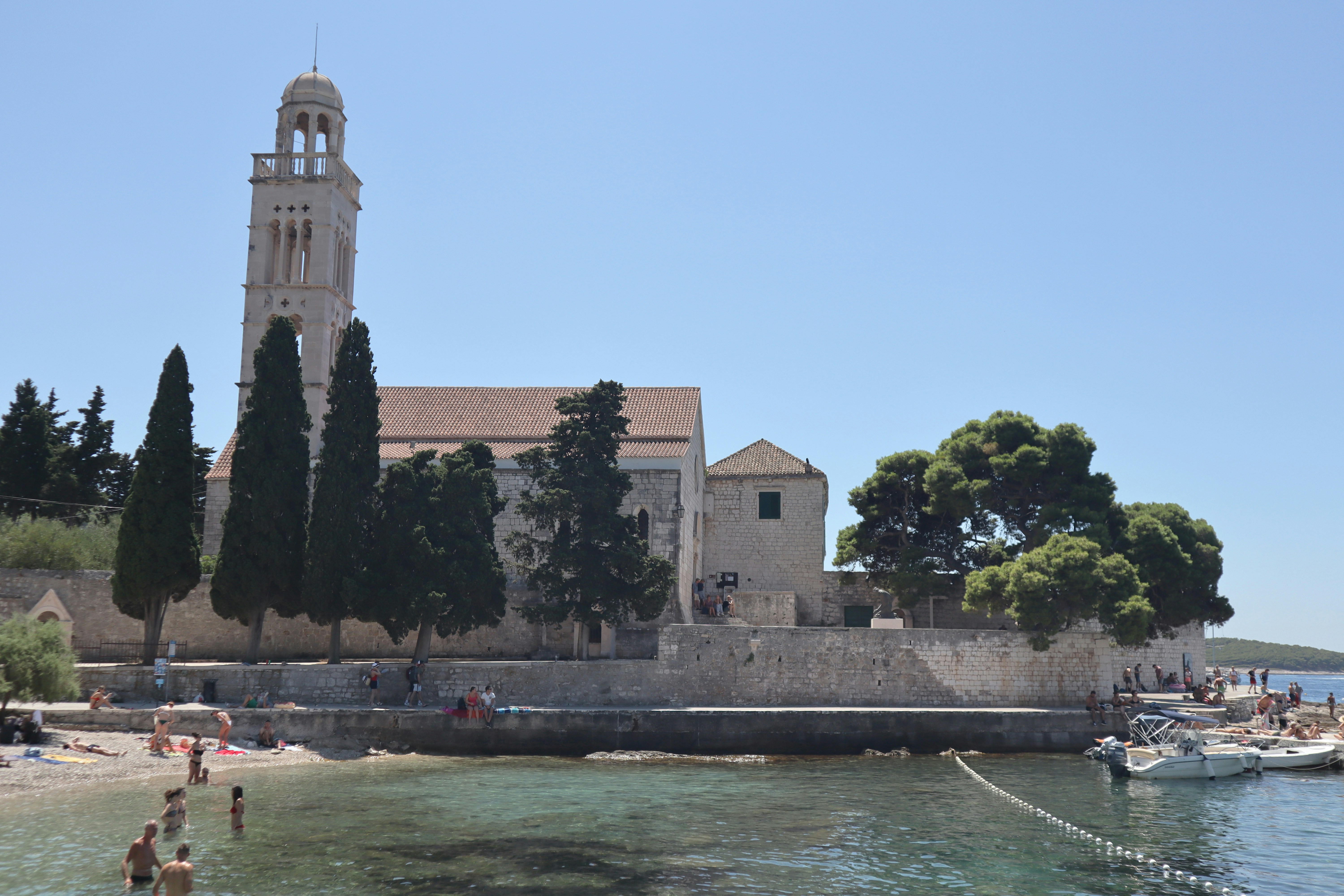 Harbor Basilica: Stone Bell Tower Framed by Cypress and Sea