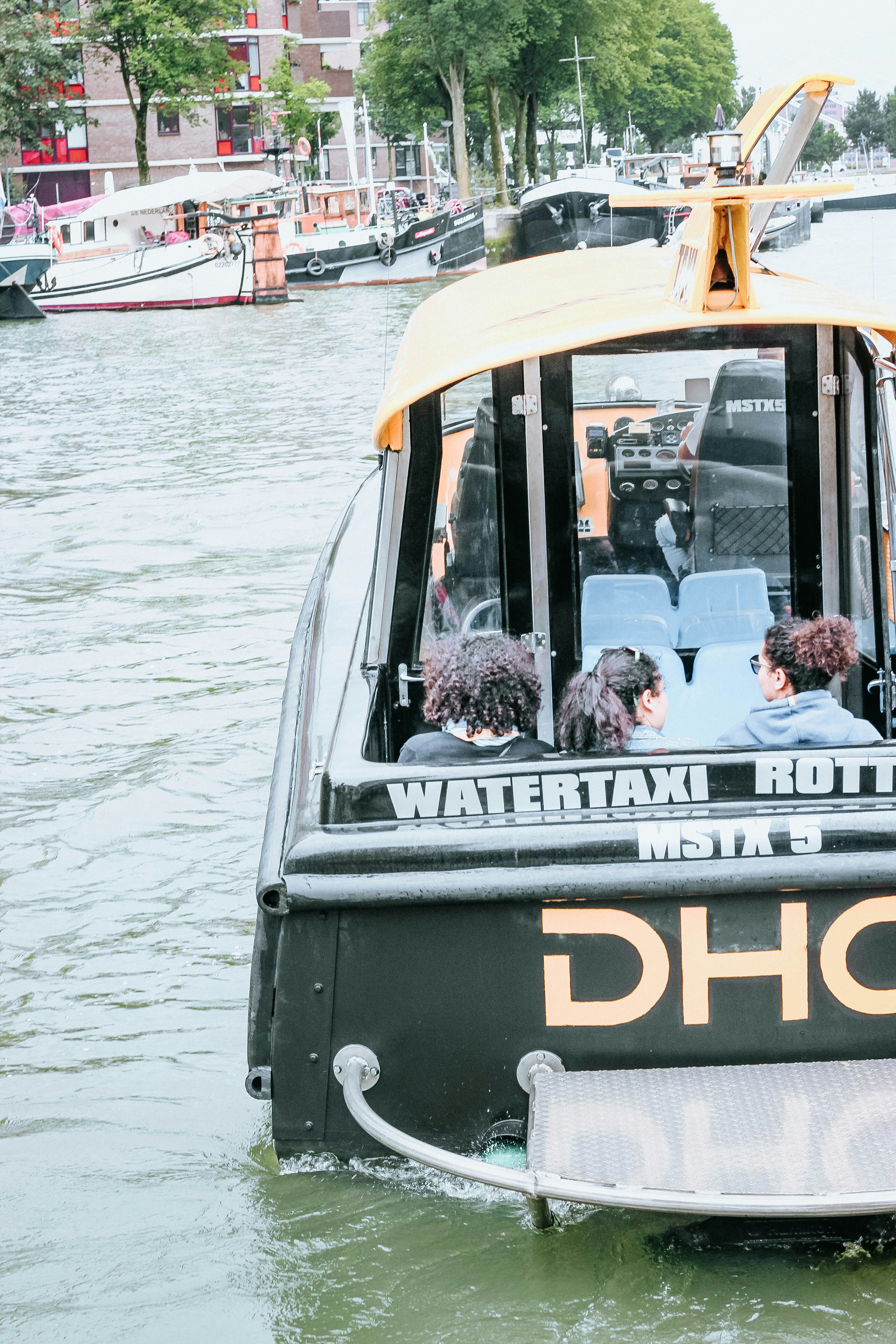 Glass-Walled Water Taxi Slips Past City Boats on a Busy Canal