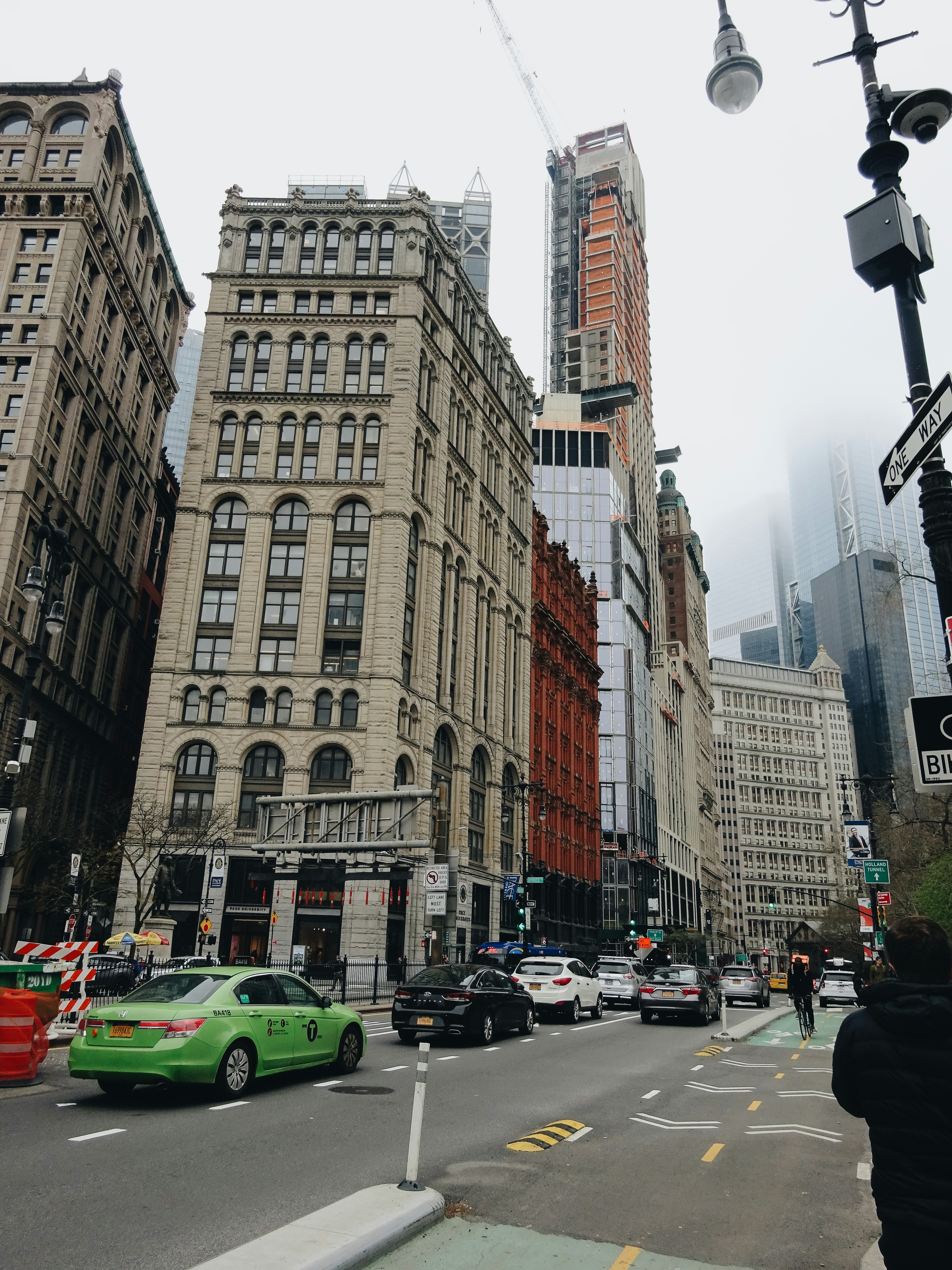 Historic buildings stand alongside modern skyscrapers in a bustling city street, showcasing architectural contrast and urban life.
