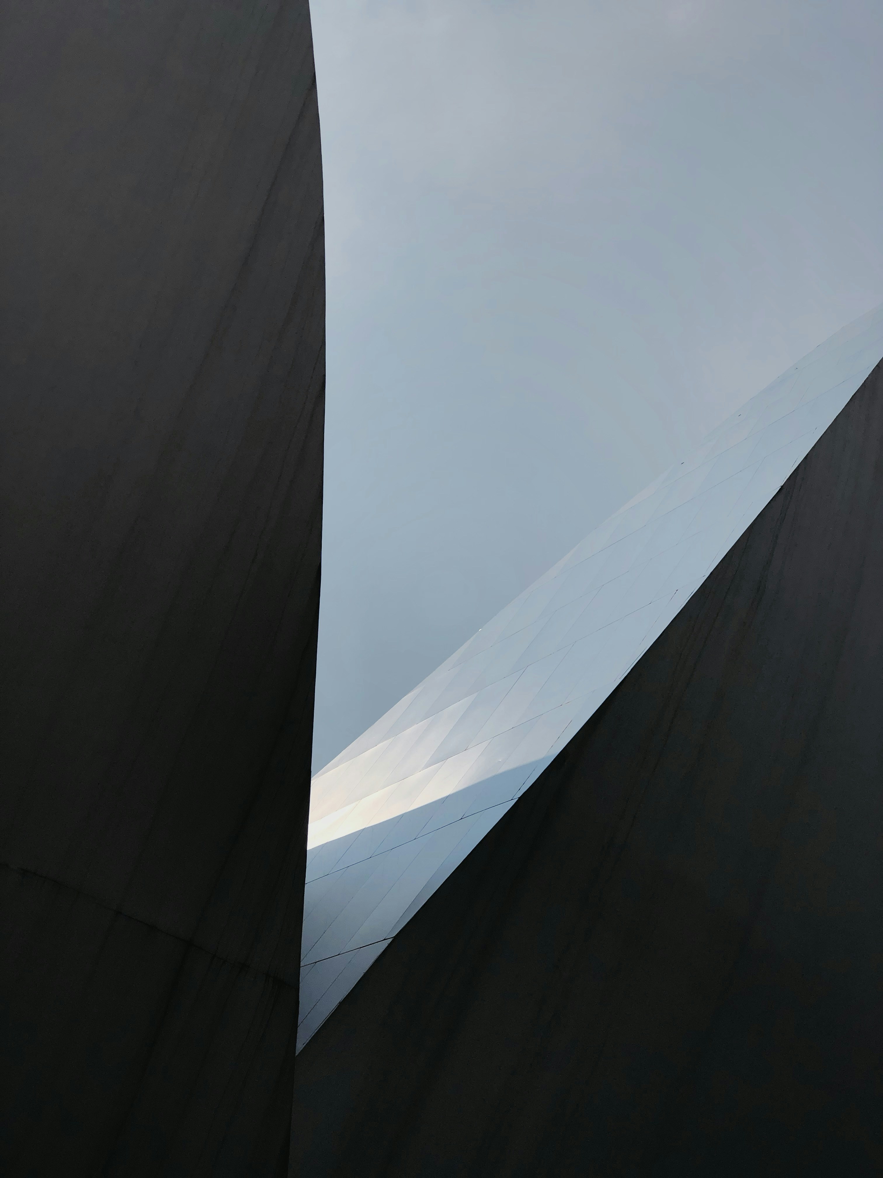 Abstract architectural forms converge, revealing sharp angles and contrasting textures under soft daylight.