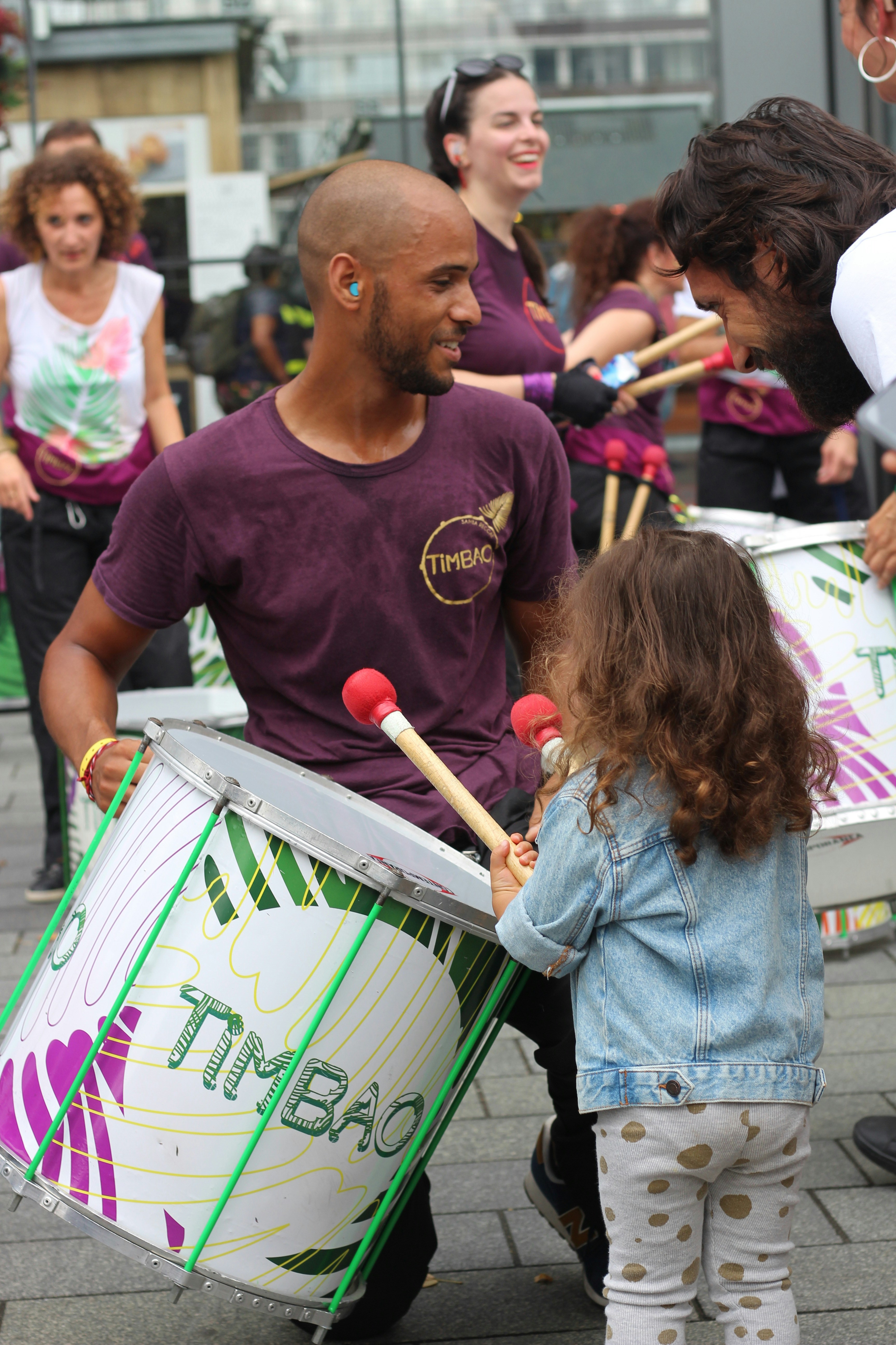 Drumming duet: a child guides the rhythm beside a drummer in a lively street performance