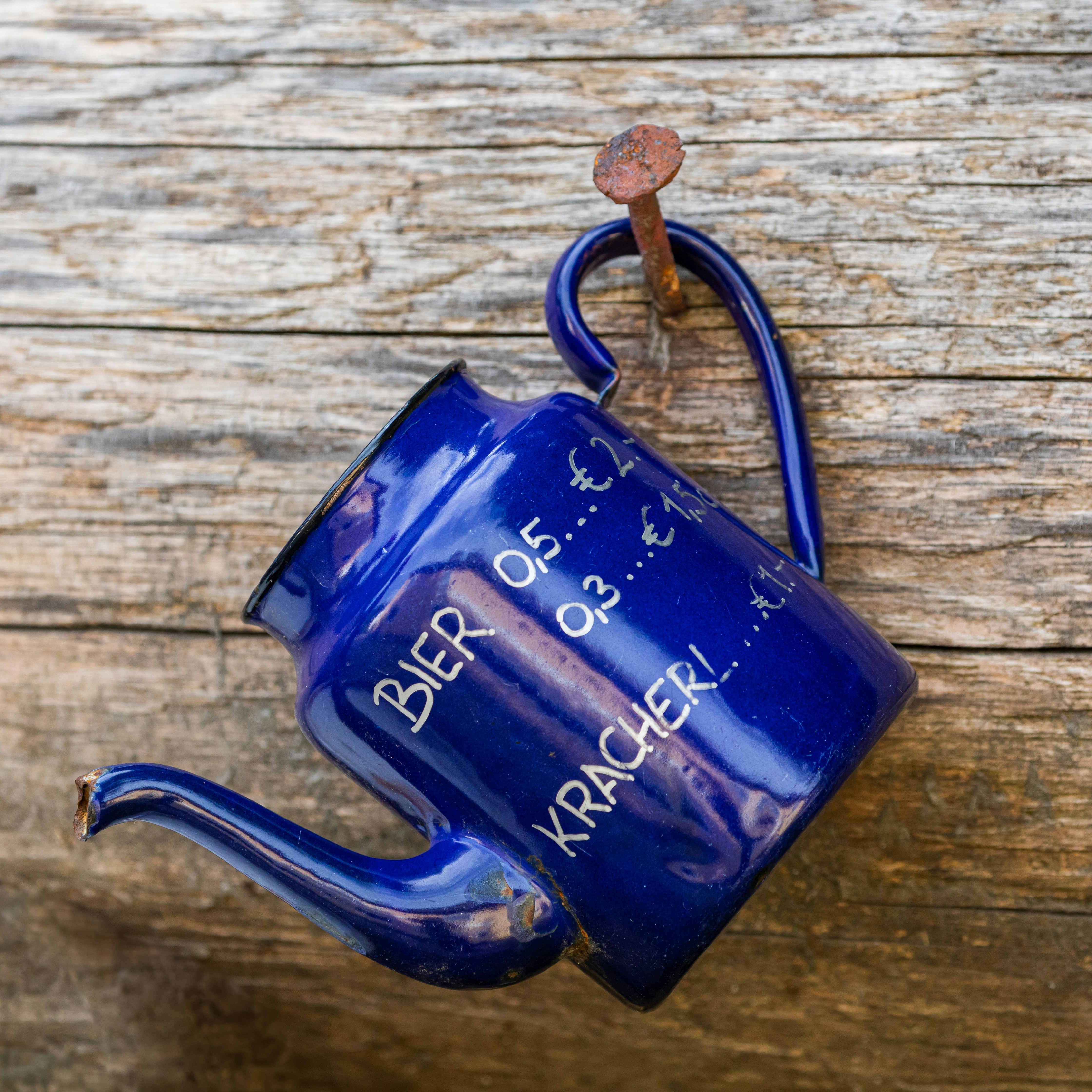 A Weathered Blue Kettle with Rusted Bolt on Rustic Wood
