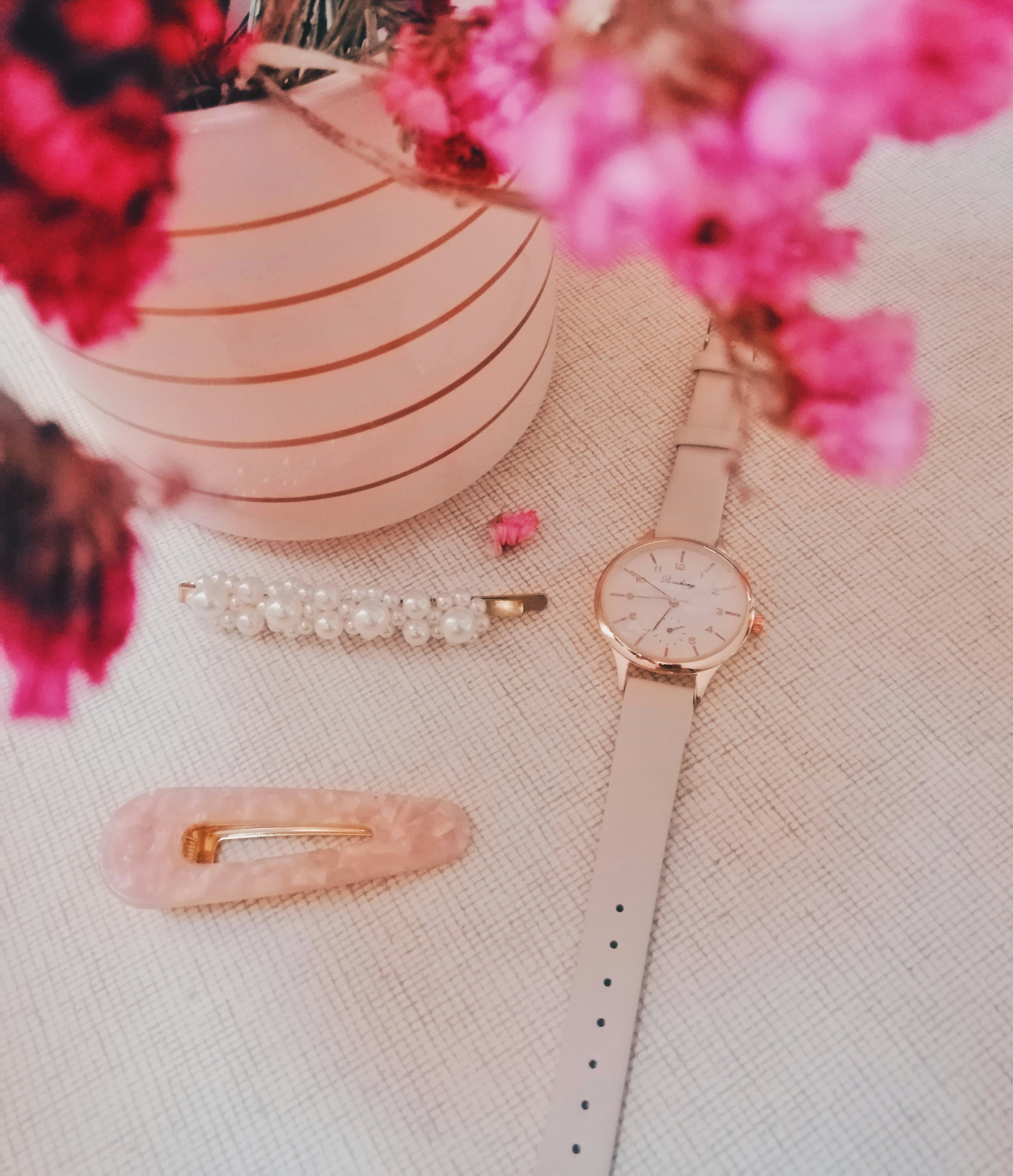 Soft-focus arrangement: a rose-gold watch and accessories on pale linen