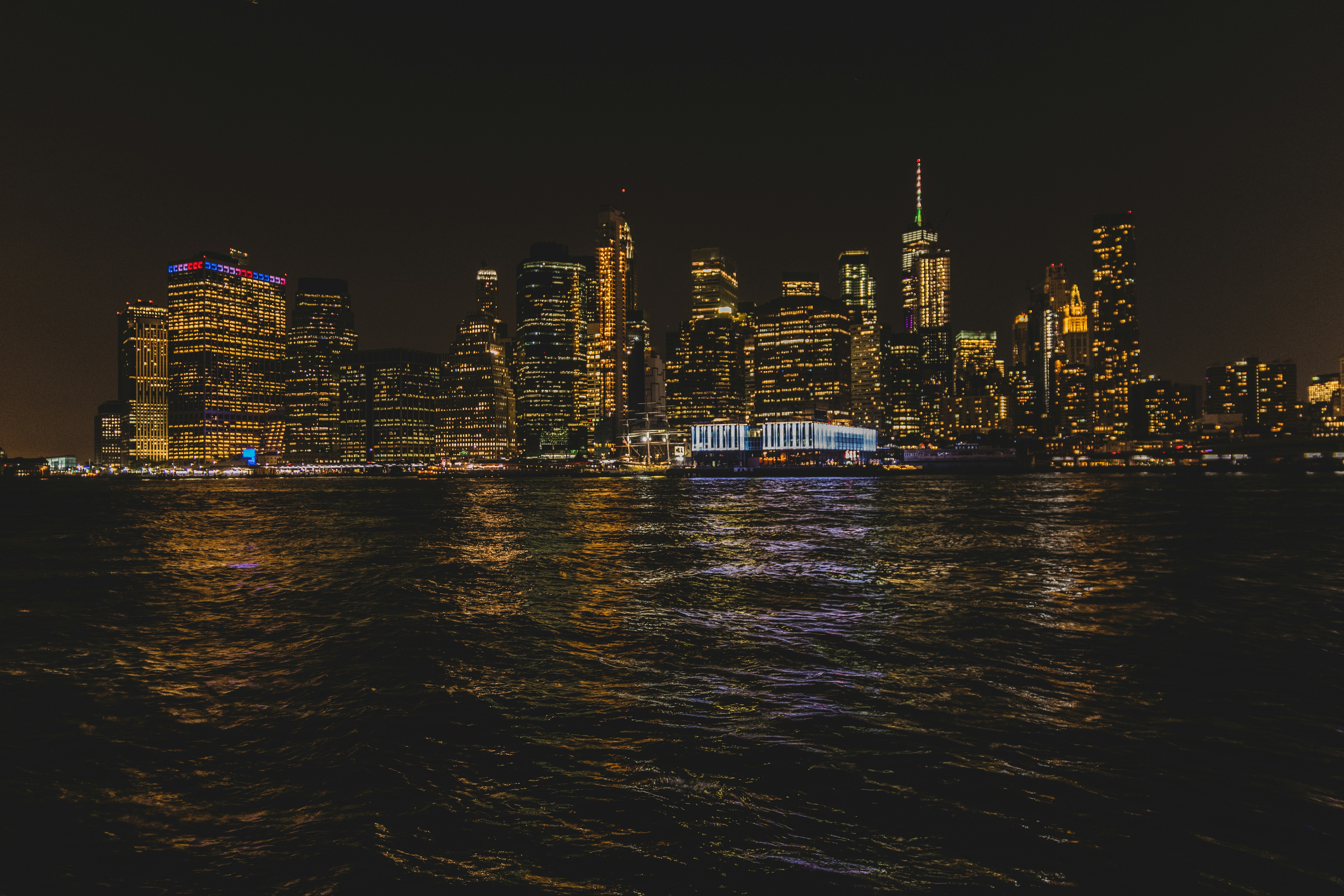 The many lights of Manhattan seen from Brooklyn | wavy body of water at night