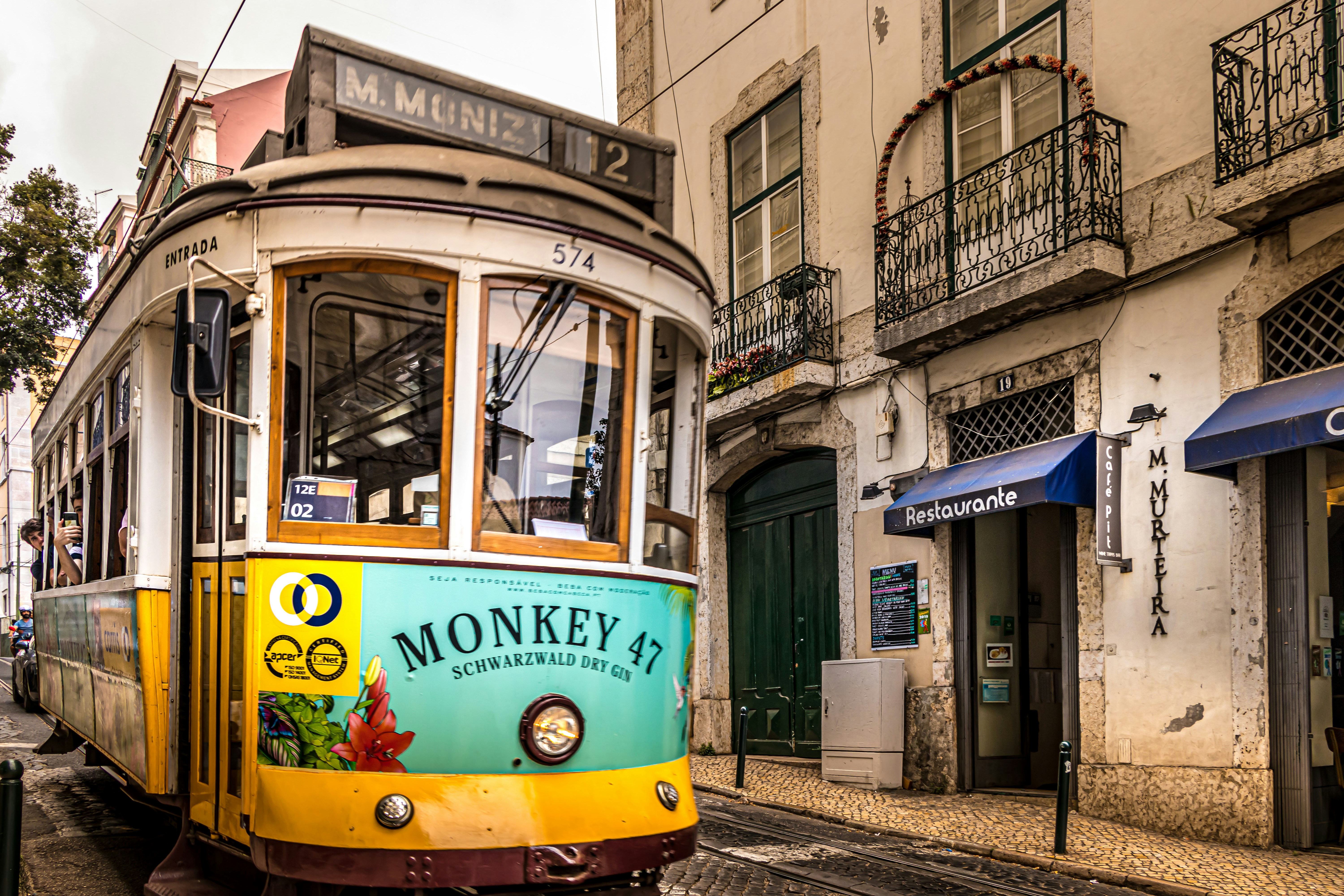 Monkey on Rails: A Sunlit Lisbon Tram Gliding Past Weathered Facades