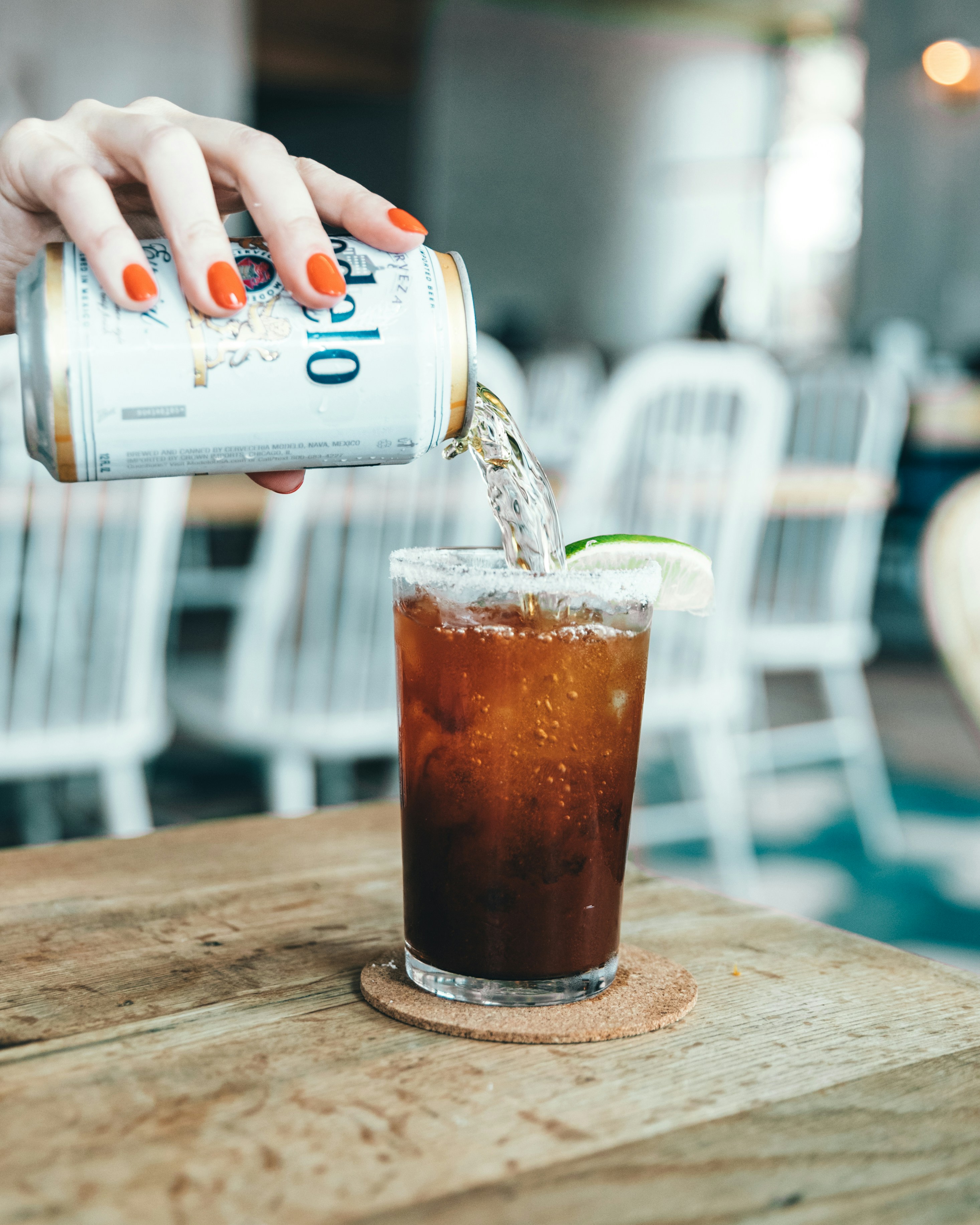 Sunlit Pour at a Rustic Café Table: Lime-Wedge Beer in a Tall Glass