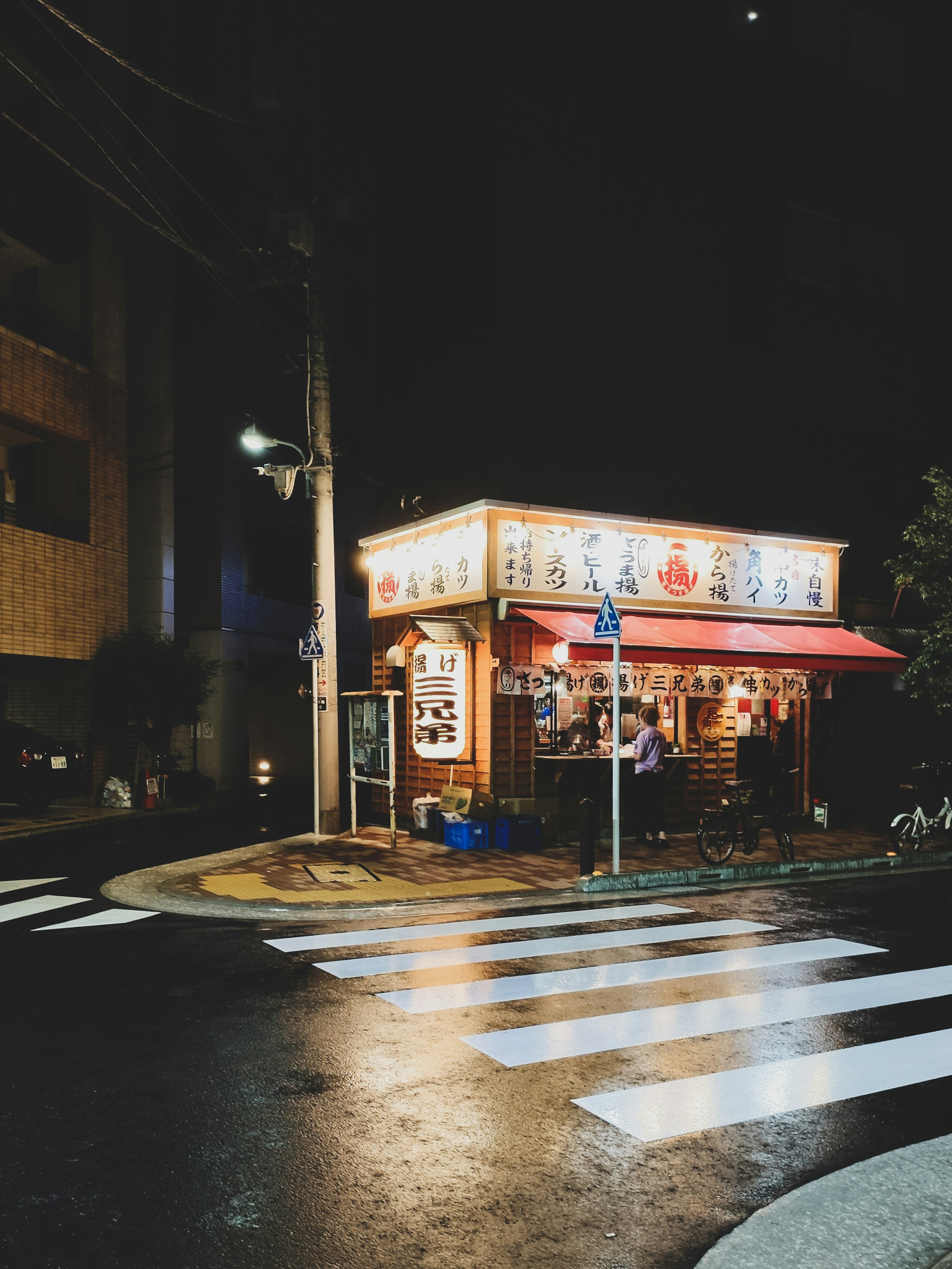 A vibrant street food stall illuminated by neon lights, showcasing a bustling night scene in an urban setting. The inviting atmosphere draws in passersby seeking a late-night snack.