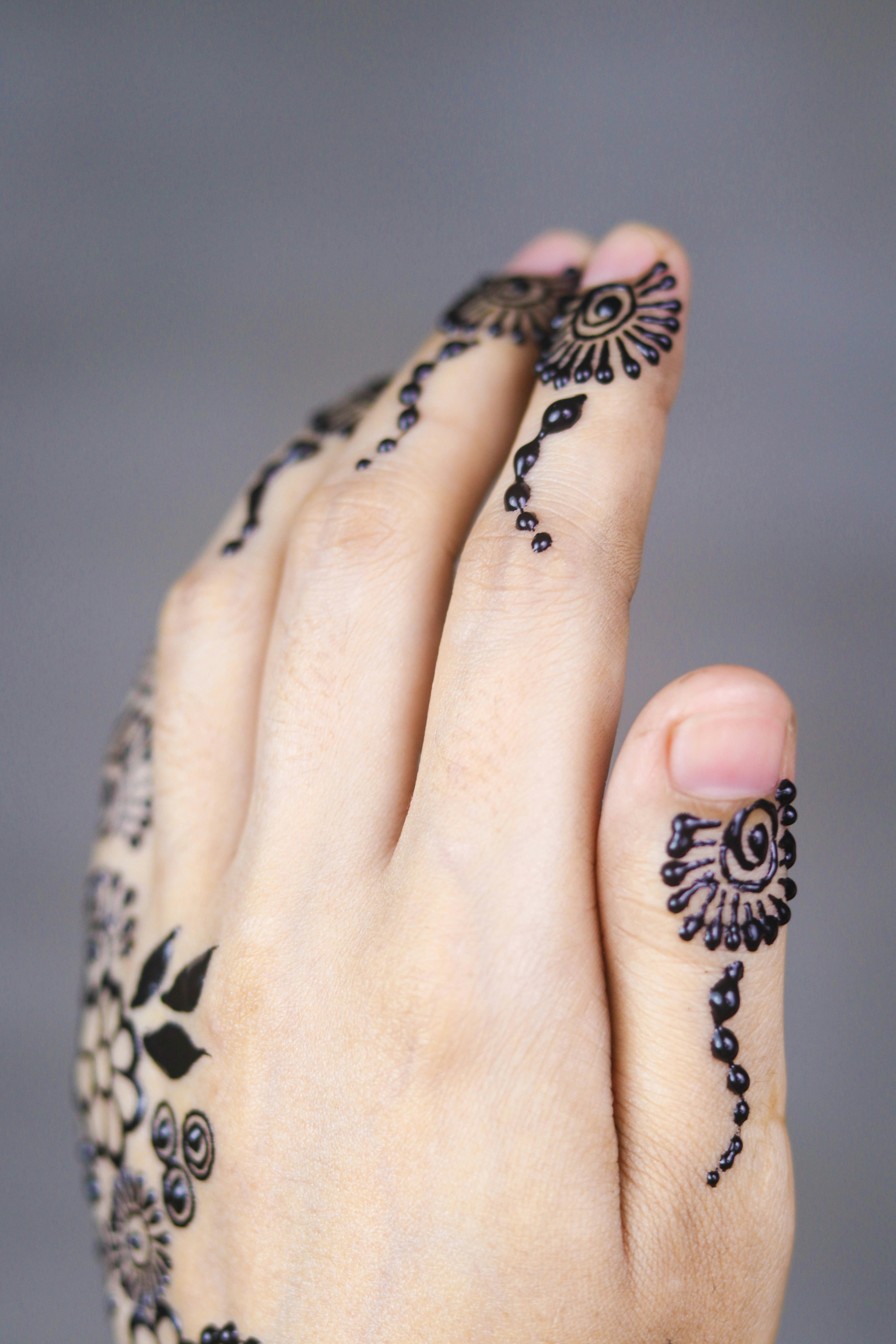 Detailed henna designs adorning a hand, showcasing intricate floral motifs and swirls. The artwork highlights cultural artistry and personal expression.