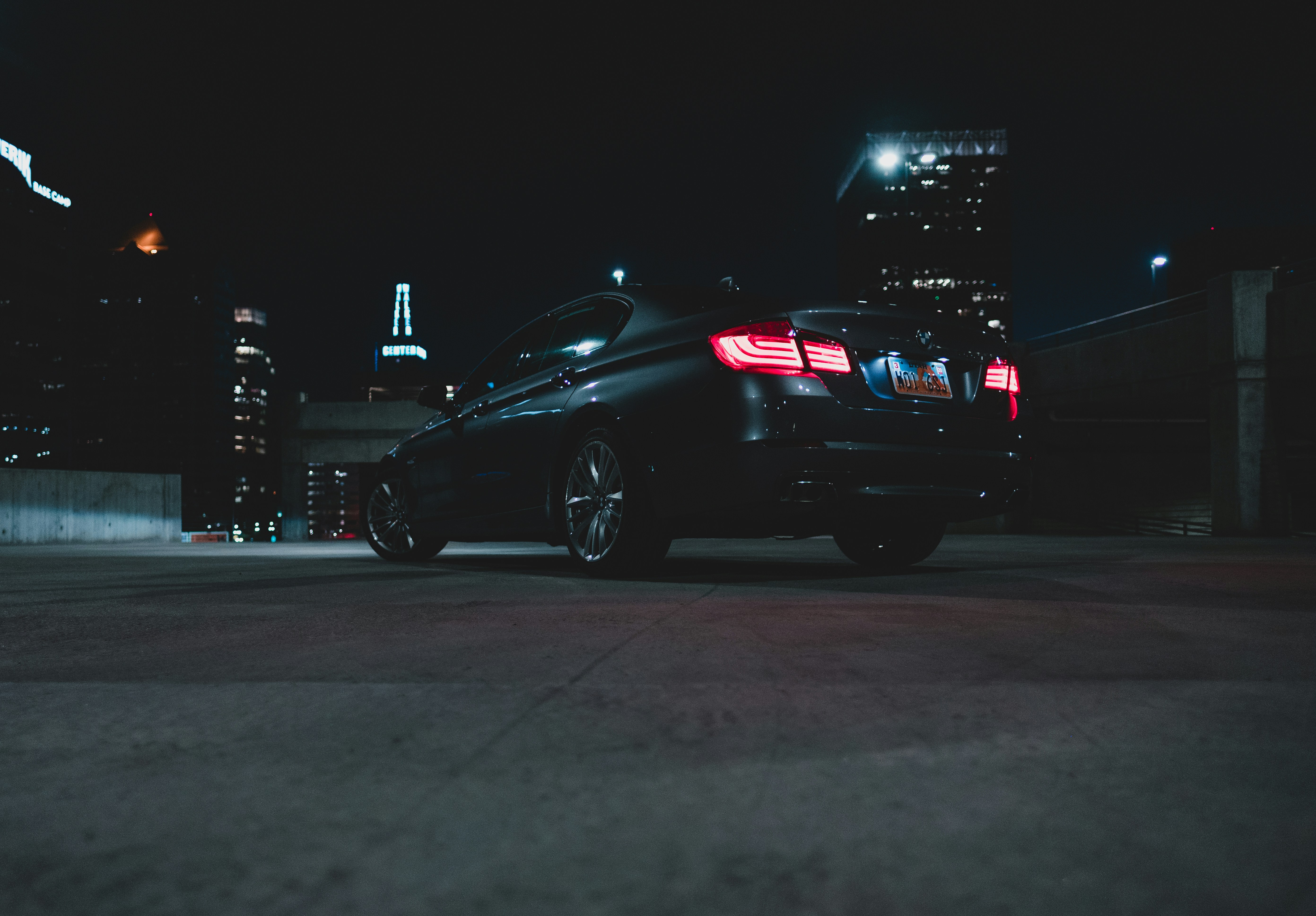Sleek car parked on a rooftop at night, city skyline illuminated in the background.