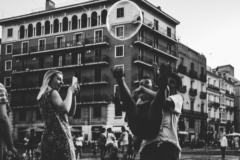 Grayscale photography of woman taking photo of man carrying another man ... Grayscale photography of woman taking photo of man carrying another man ...
