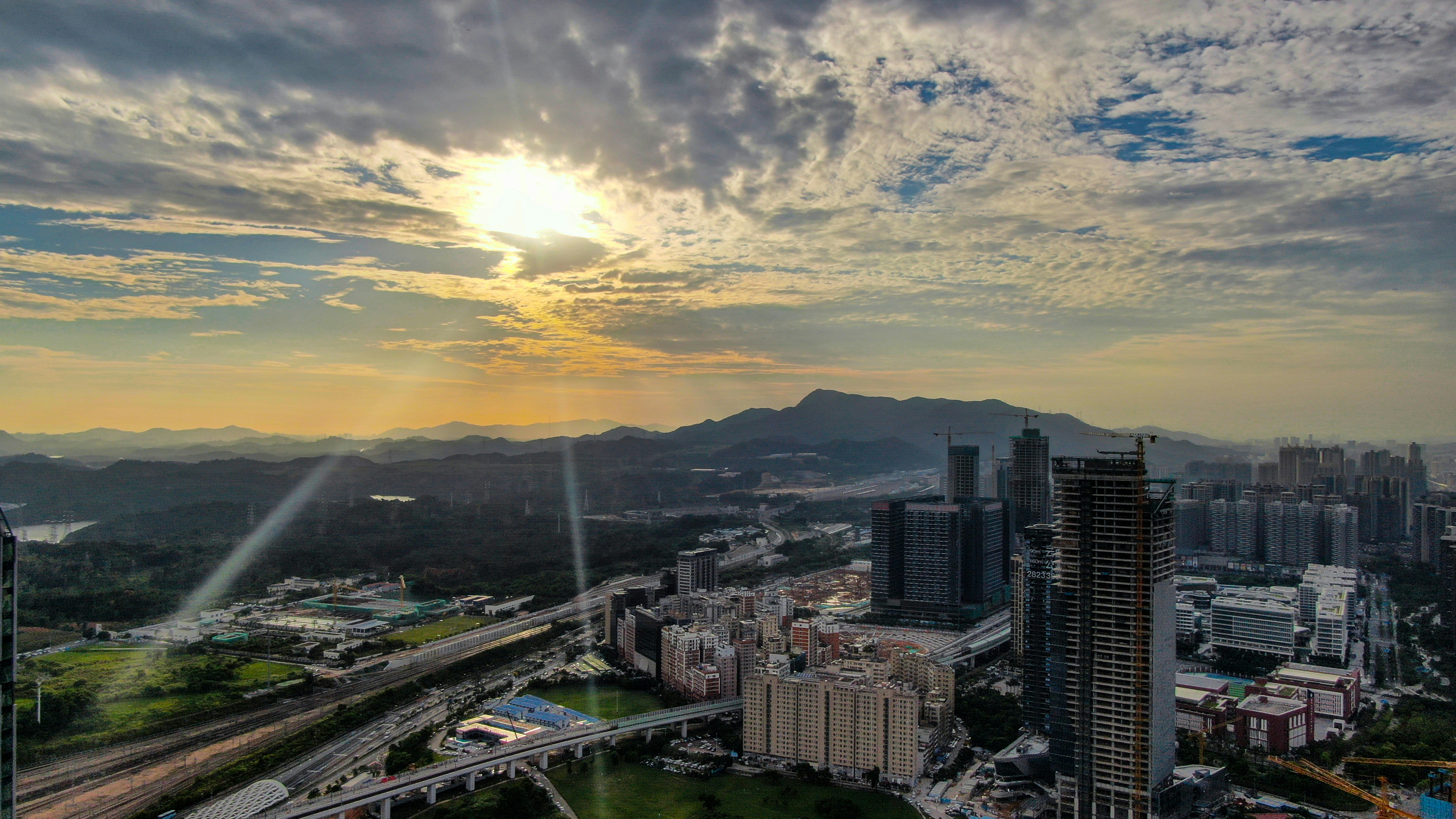 Golden rays of sunlight cascade over a sprawling cityscape, highlighting the contrast between nature and urban life. A blend of skyscrapers and lush greenery creates a dynamic visual narrative.