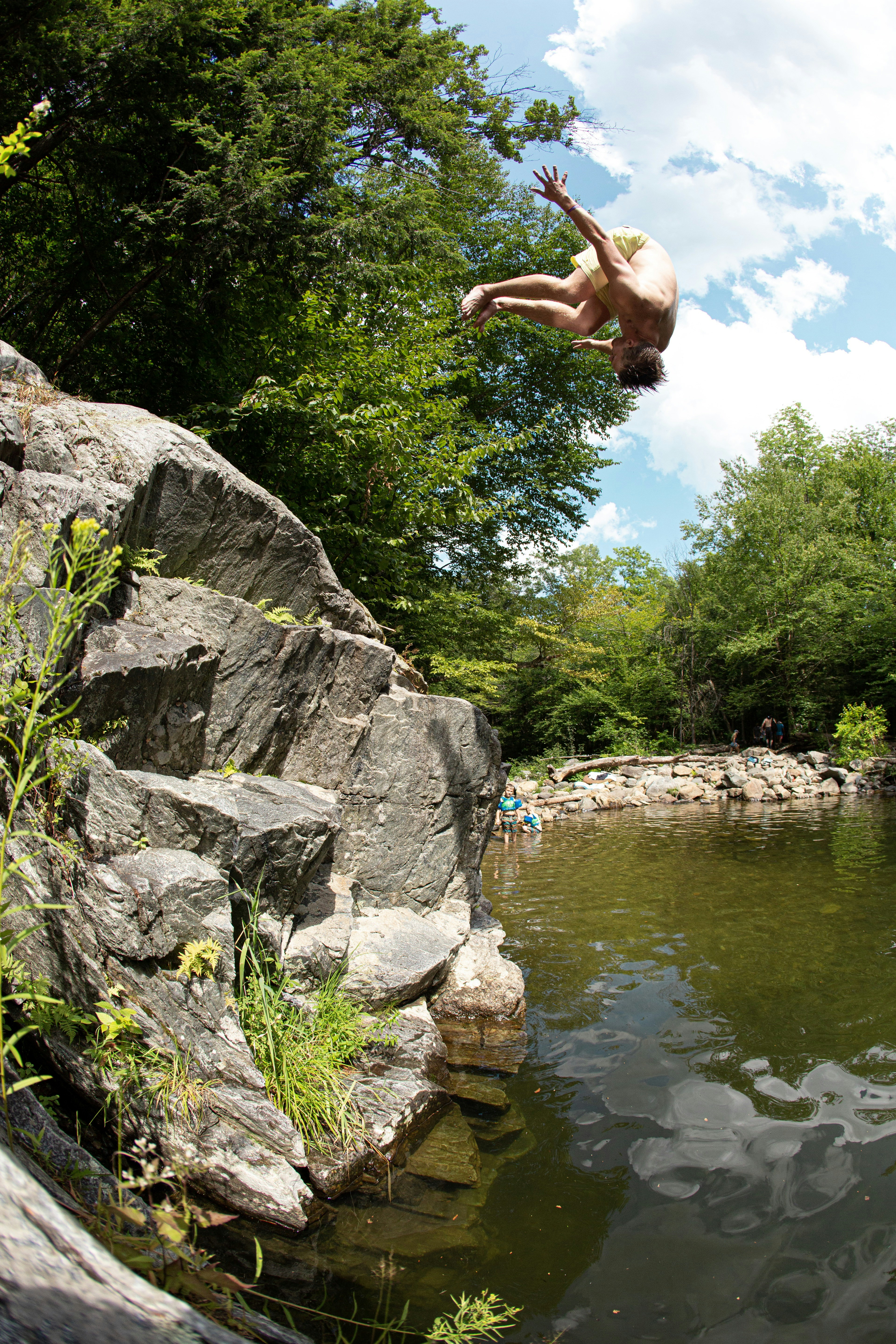 Person jumping from boulder to body of water during daytime photo ...