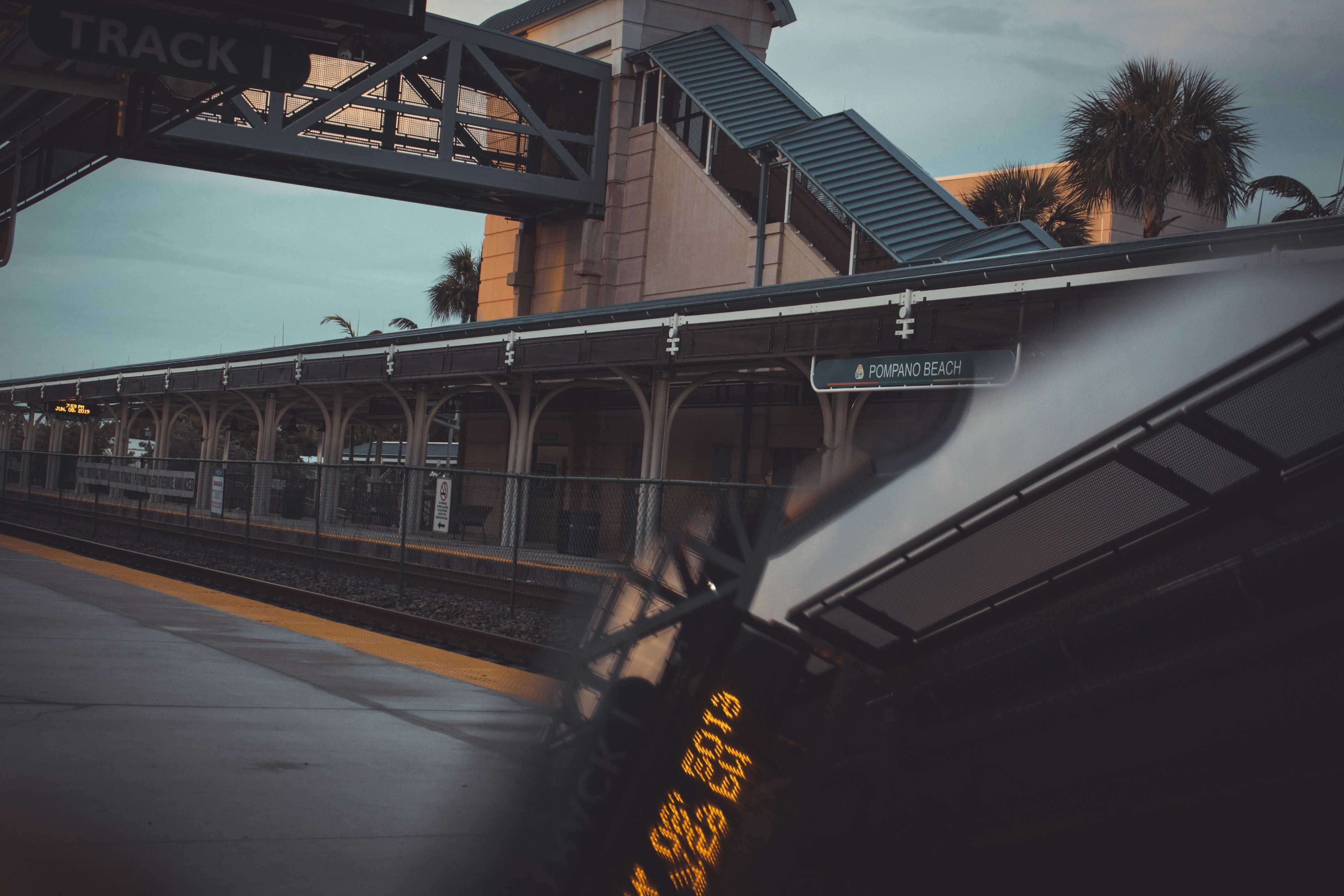 Train station platform with a blurred train departing under an overcast sky.
