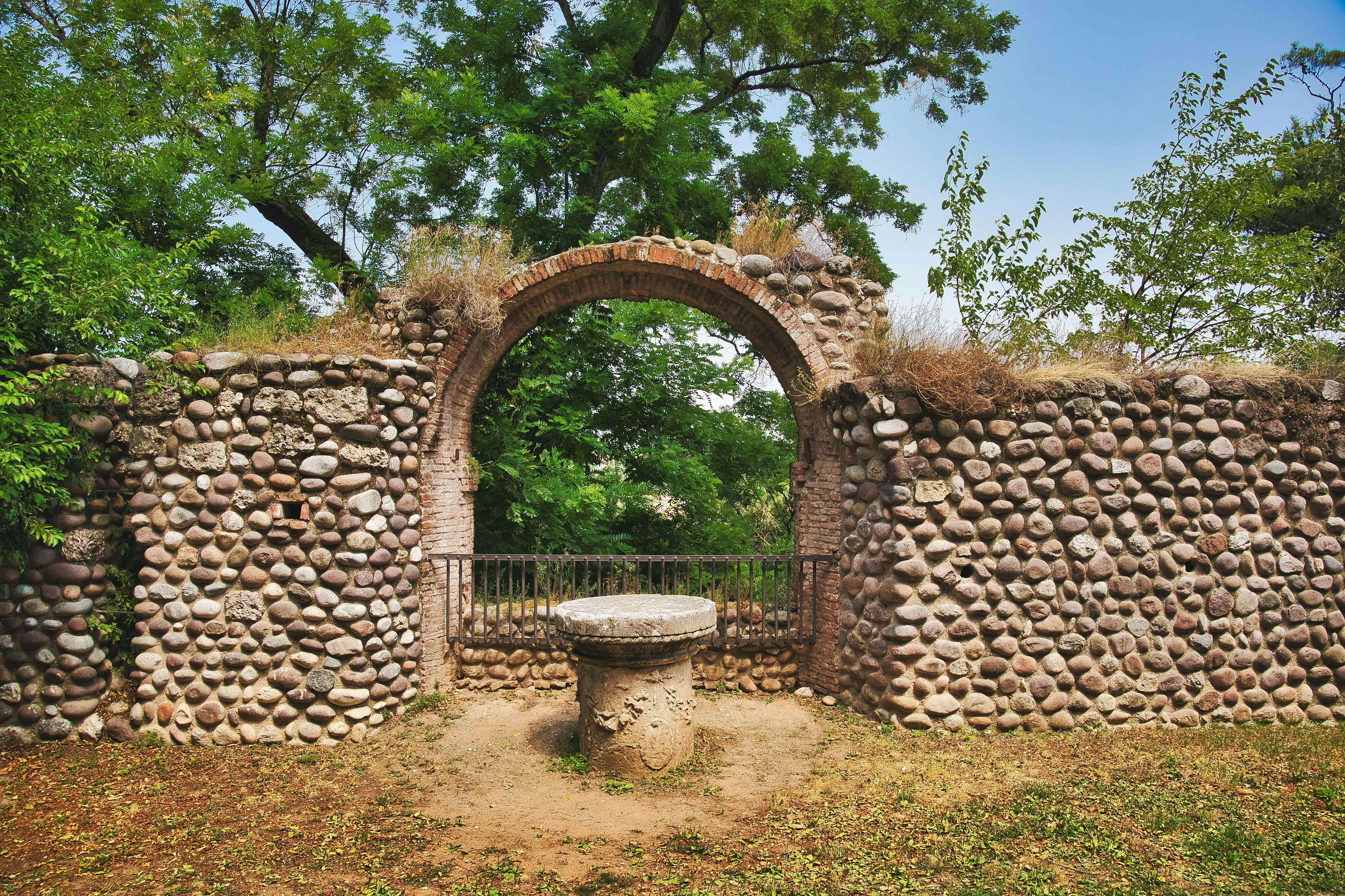 gray and brown concrete wall surrounded with tall and green trees