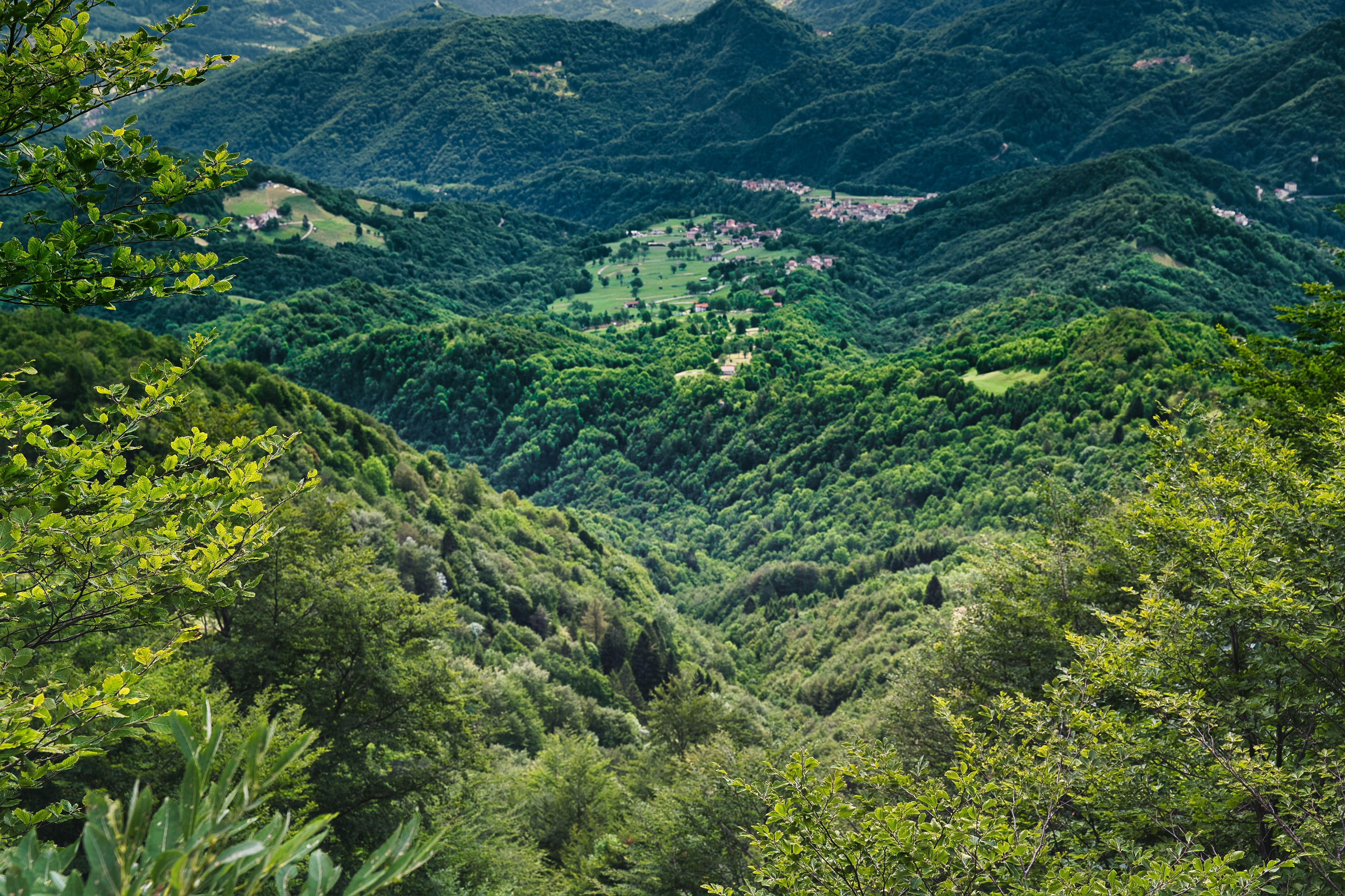 Lush green valleys stretch across the landscape, framed by rolling mountains under a clear sky. The scene captures the serene beauty of untouched nature.