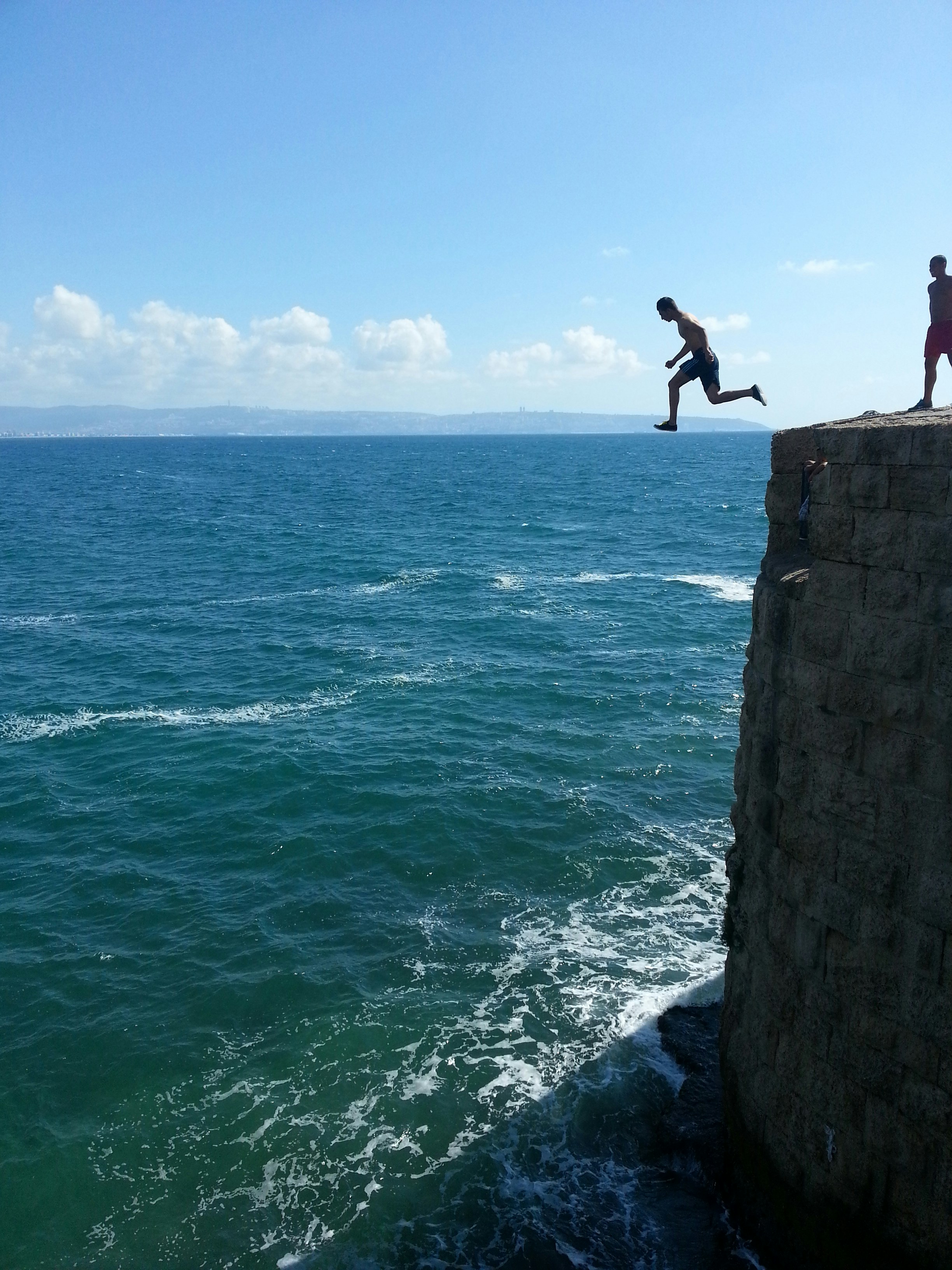 Two people jumping off a cliff into the ocean photo – Free Human Image ...