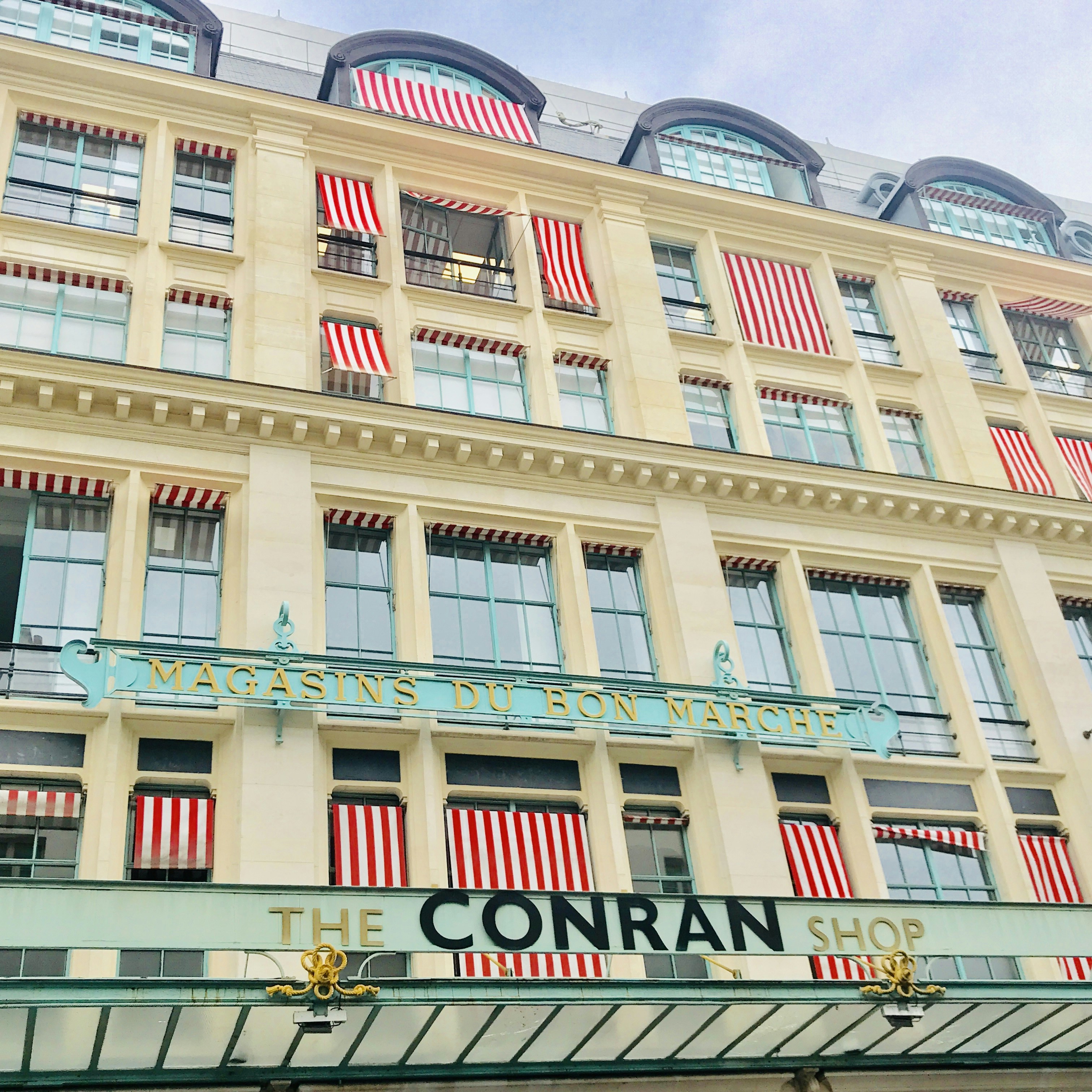 Pastel Facade and Red-Striped Awnings: A City Shopfront Portrait