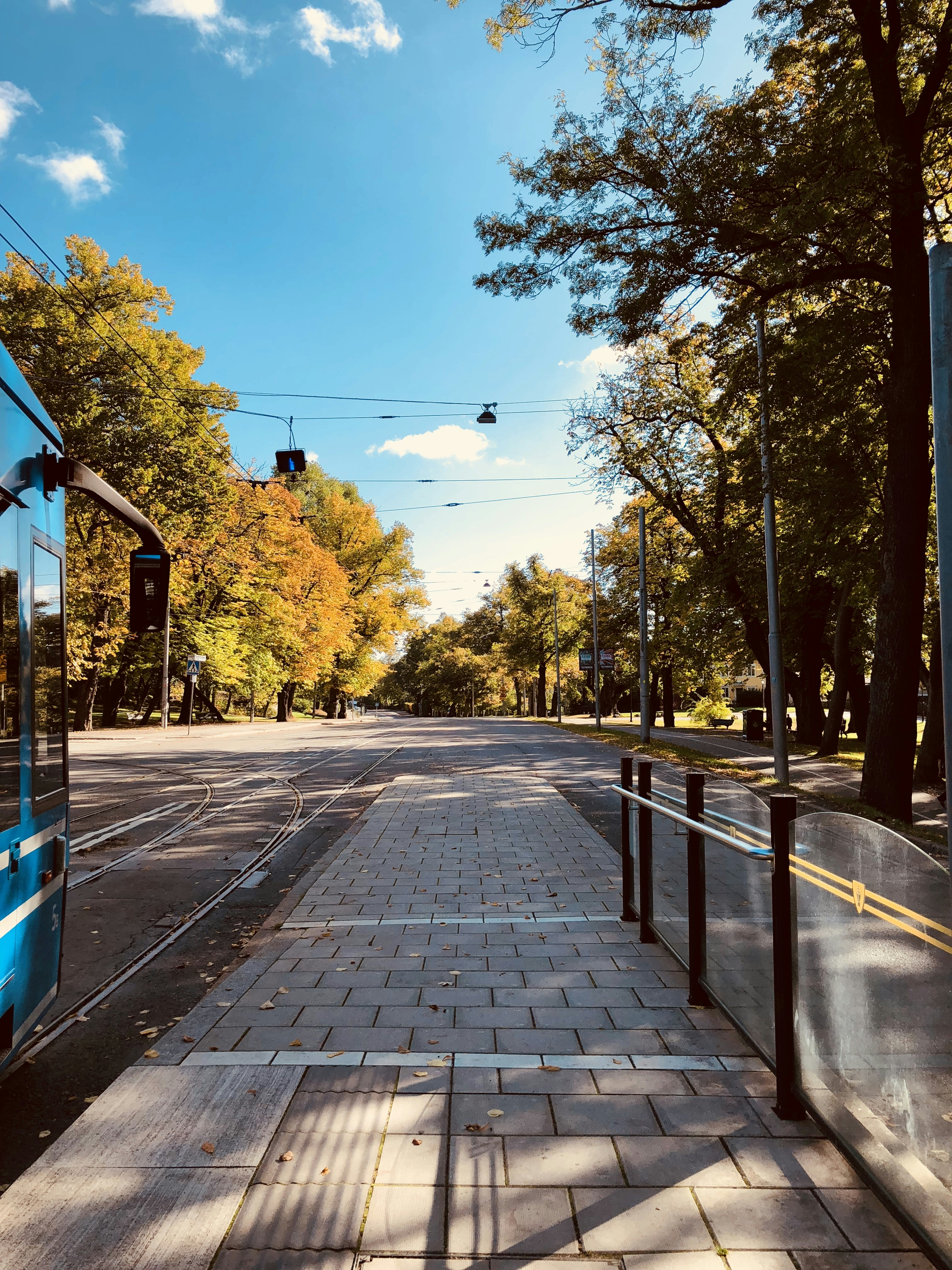 Blue Tram Beneath Autumn Light on a Quiet City Walk